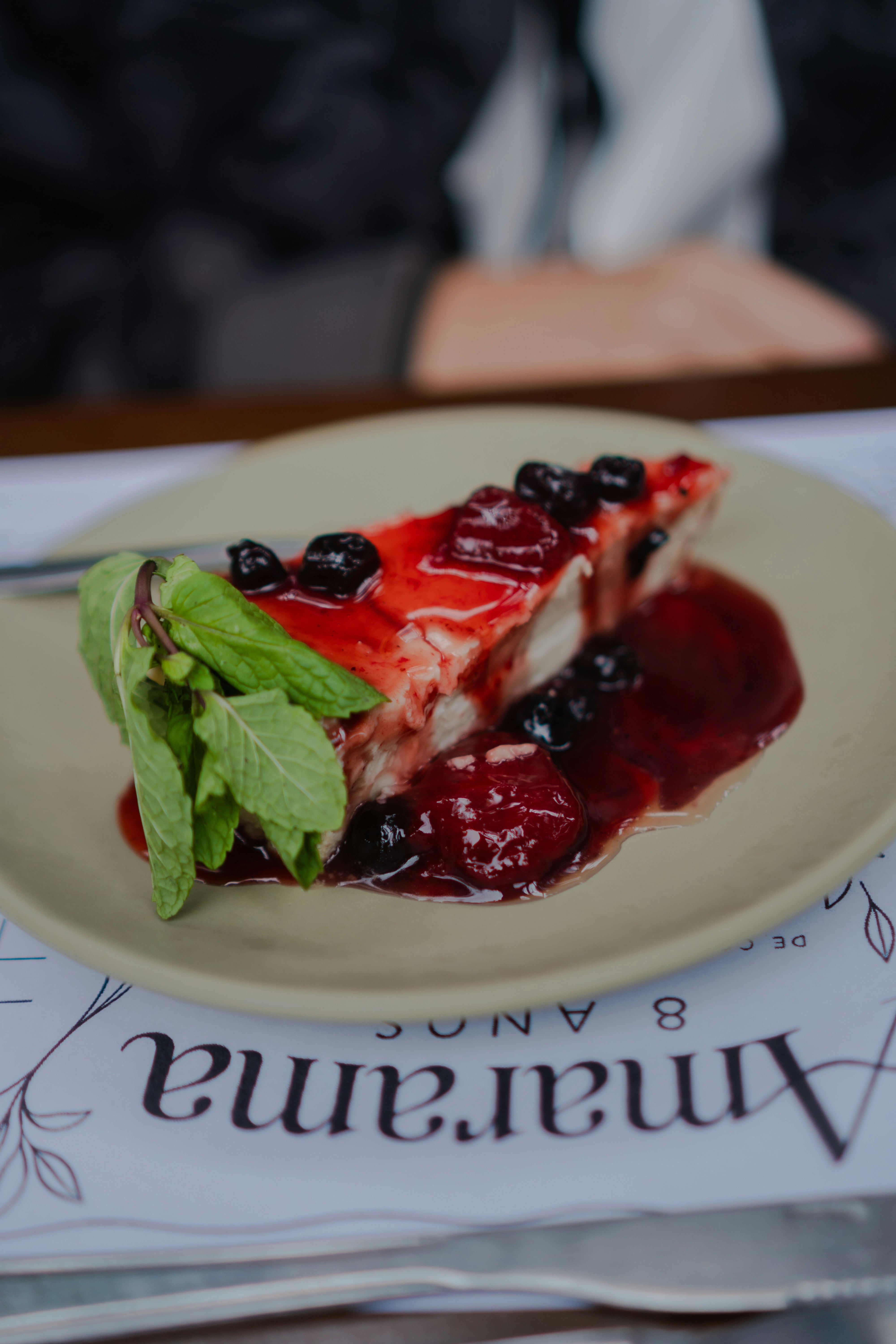 Cherry-Red Cheesecake Slice with Mint on a Cream Plate