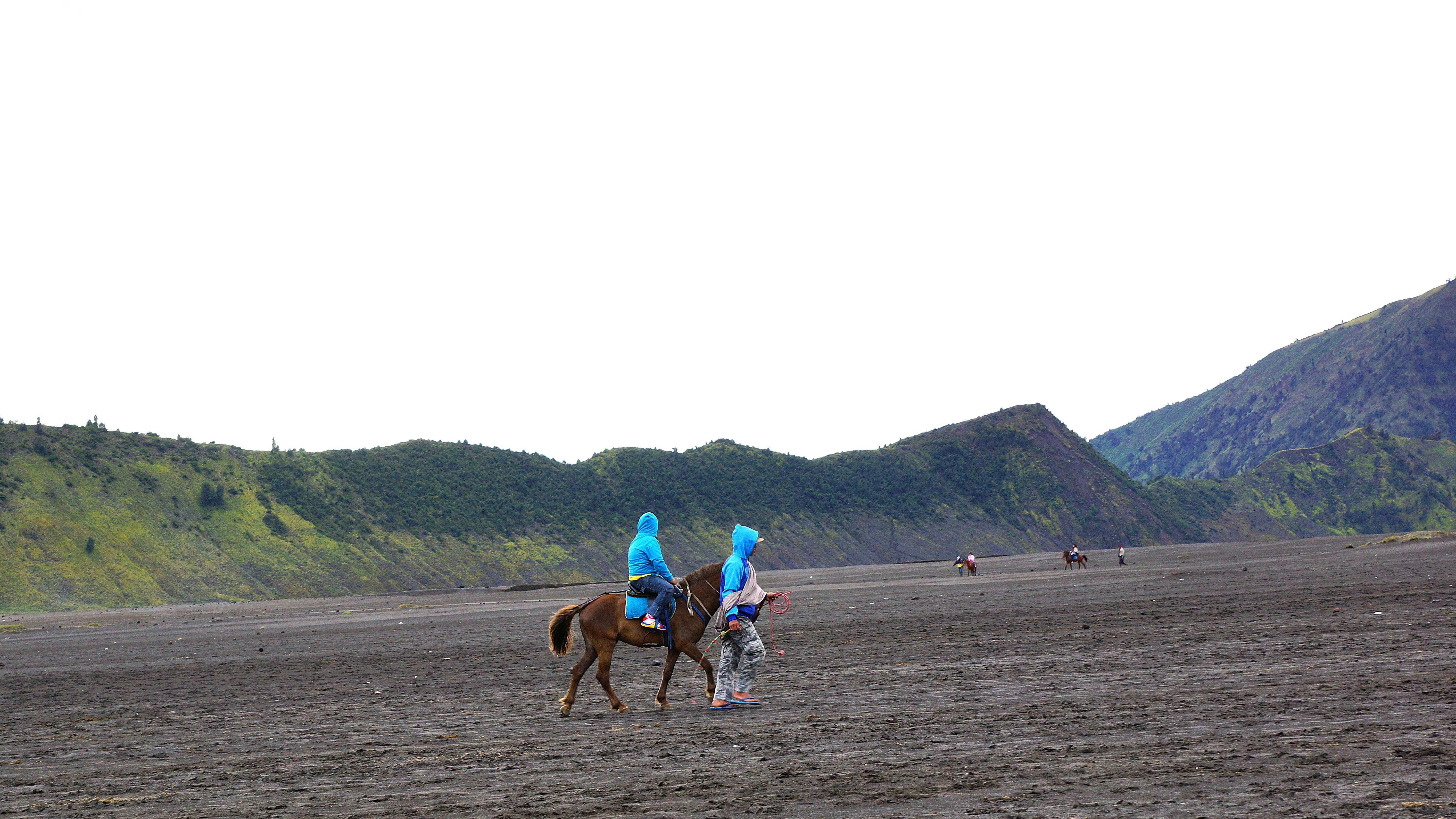 Riders in Neon Hoods Crossing a Volcanic Shoreline