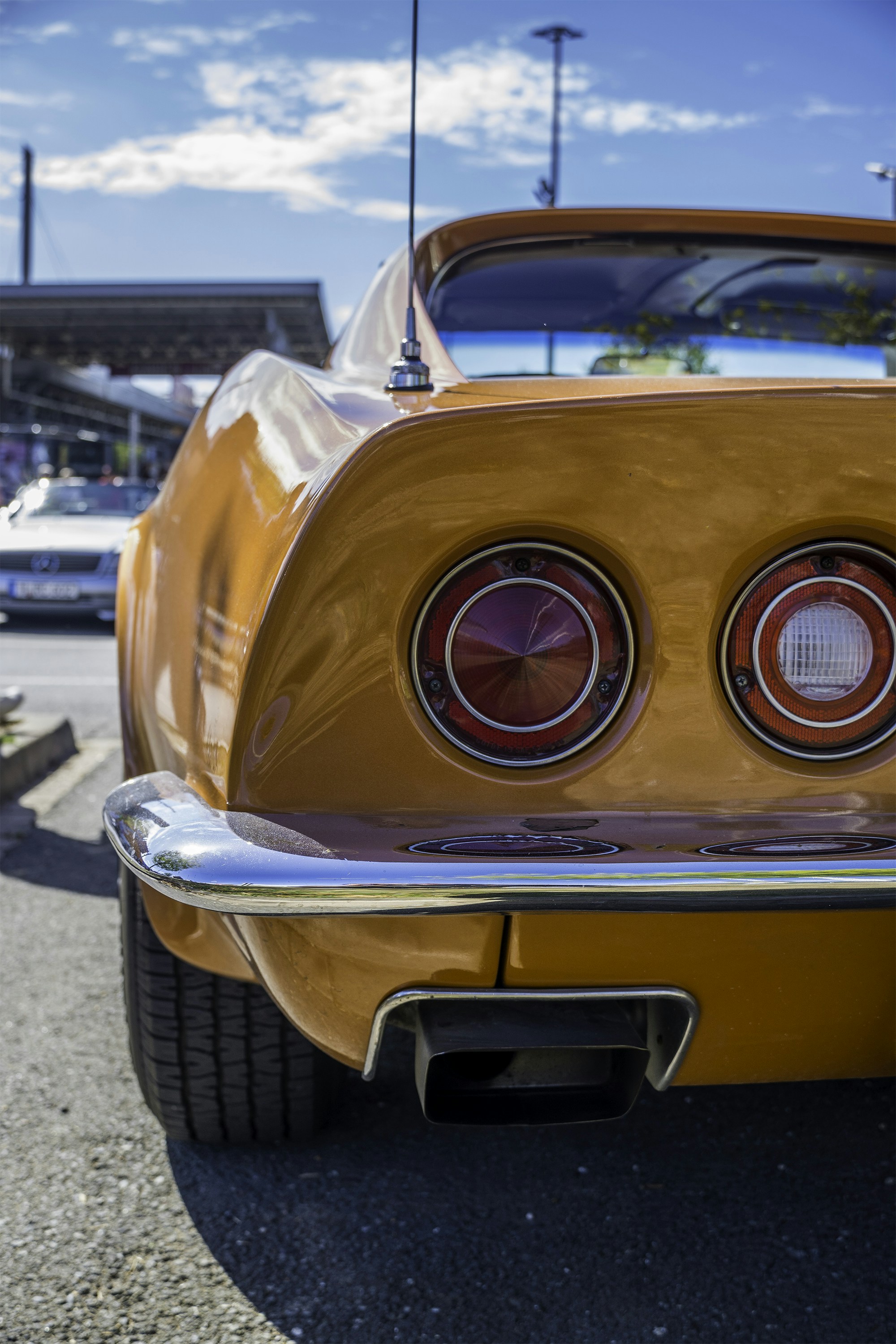 Curved Car Tail: A Sunset-Orange Classic Resting in the Lot