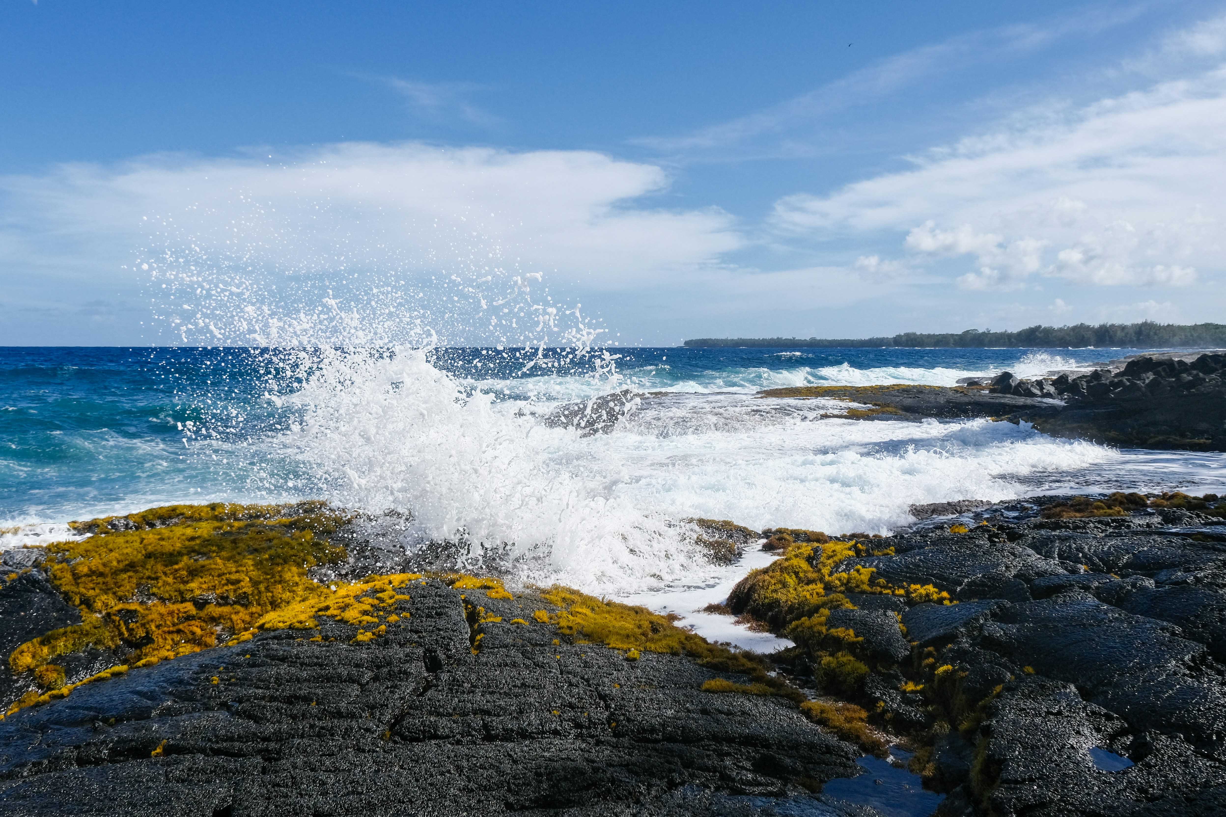 Rogue Wave Over Black Lava Rock under a Blue Sky