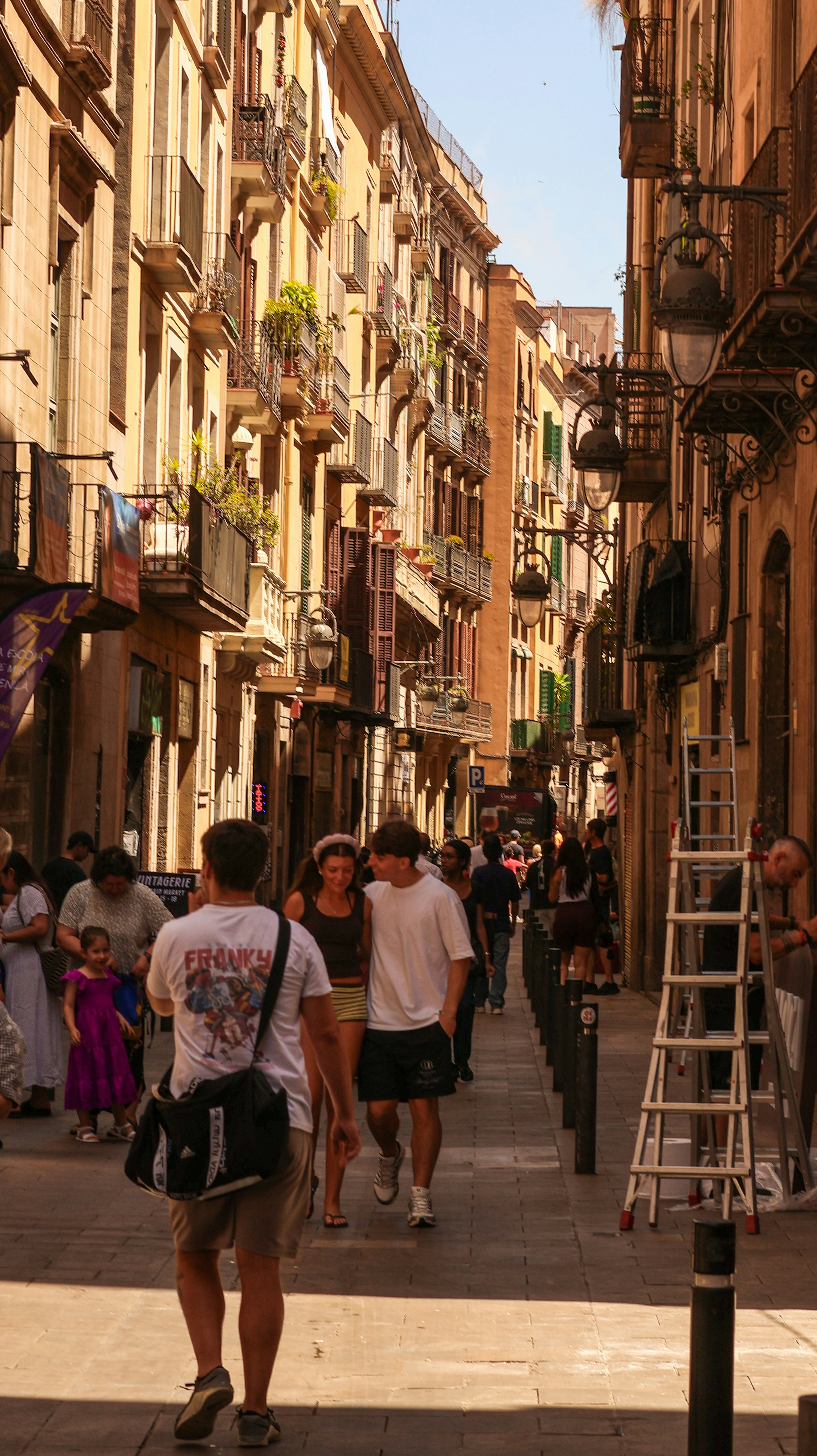 Sunlit Calle: People Stroll Through a Narrow European Street