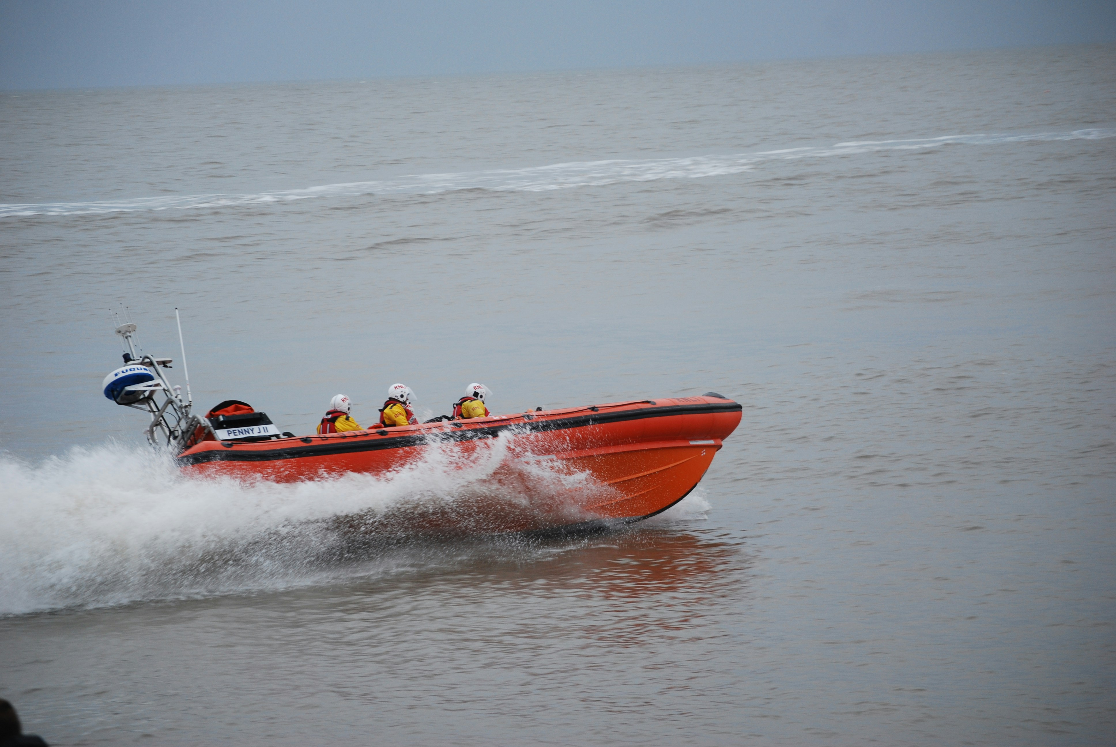 Red speedboat carving a white wake across calm sea
