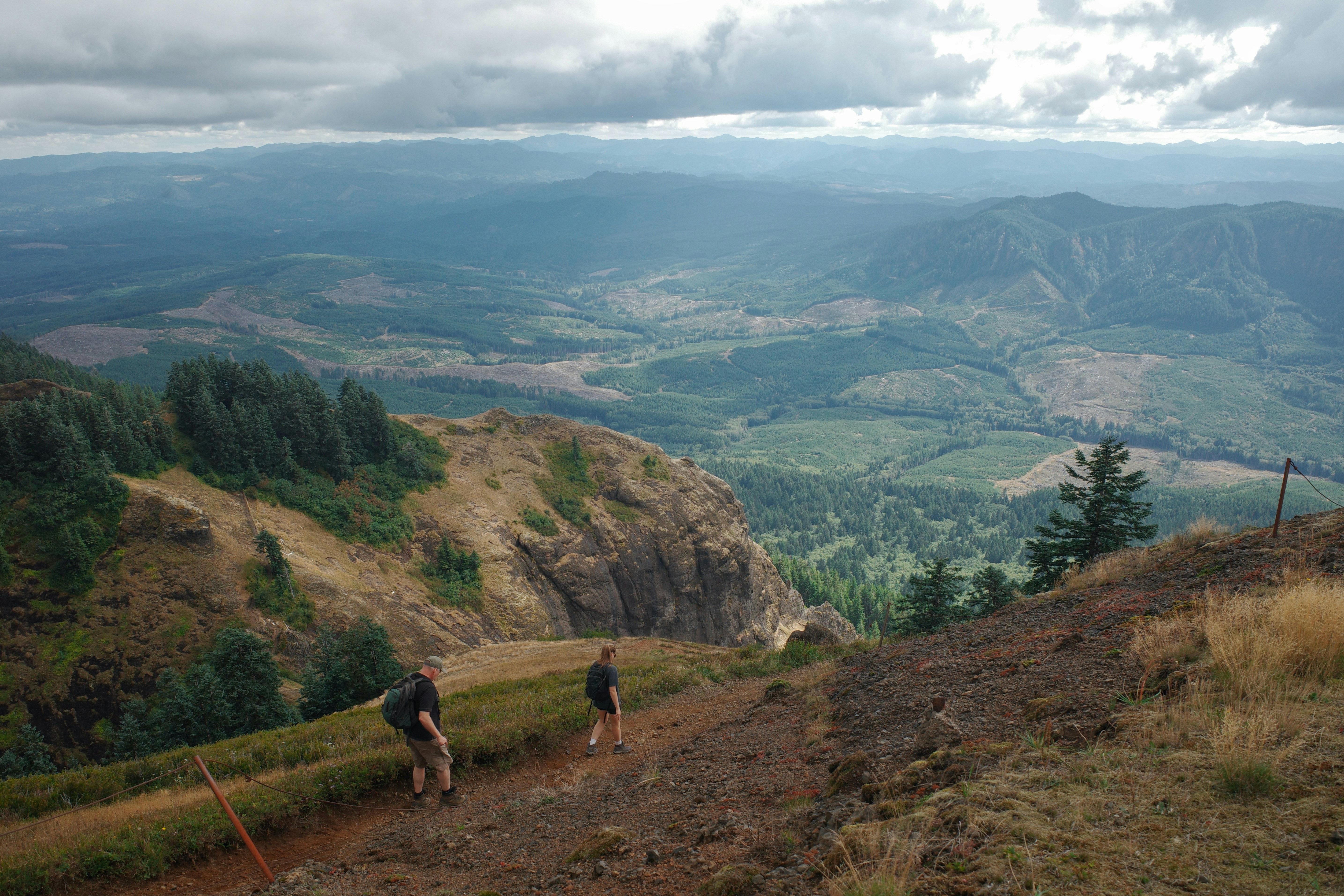 Trail Tranquility: Two hikers on a windswept ridge above a valley