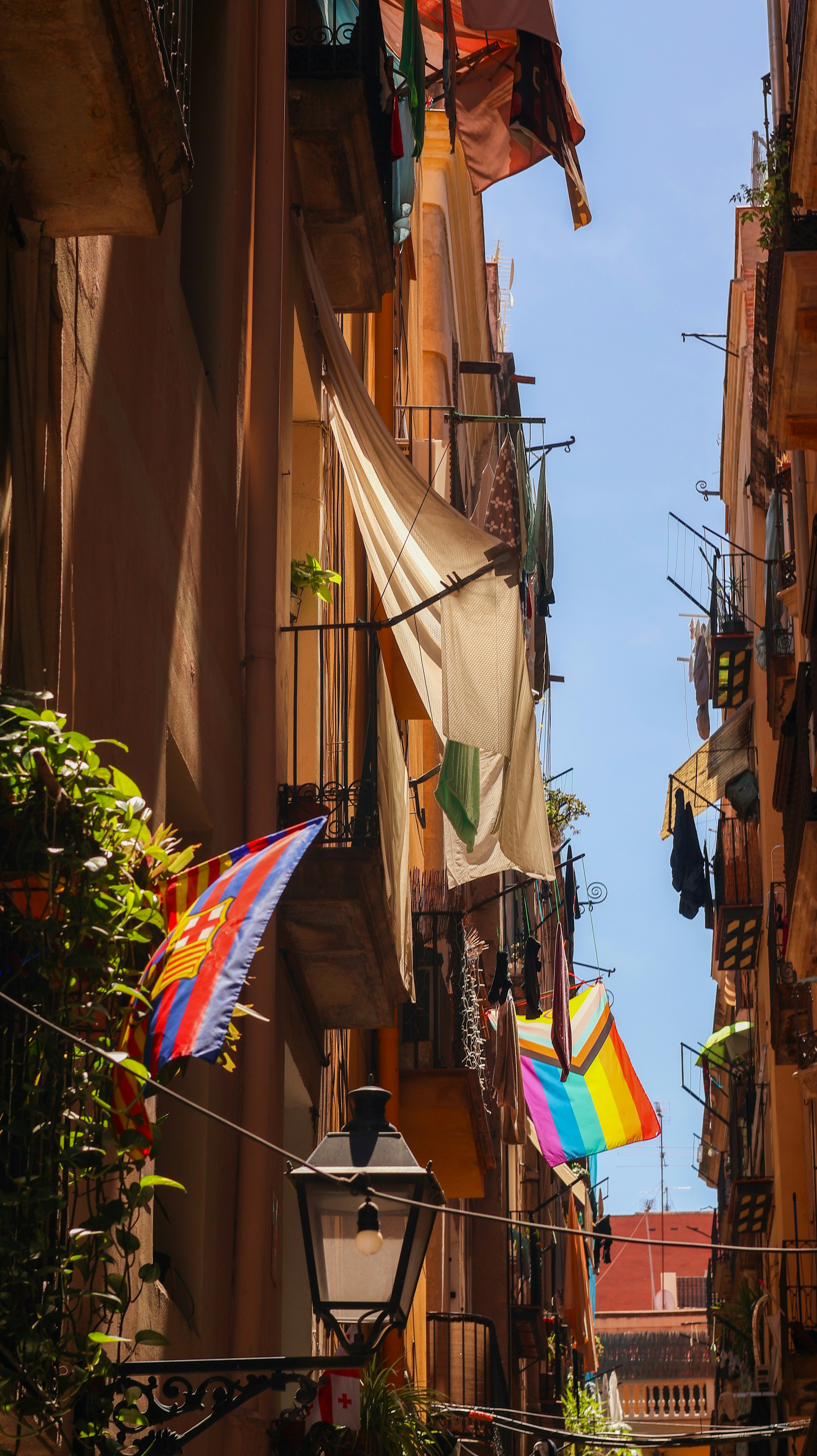 Sunlit Alley Flags: A Corridor of Color in Catalan Light