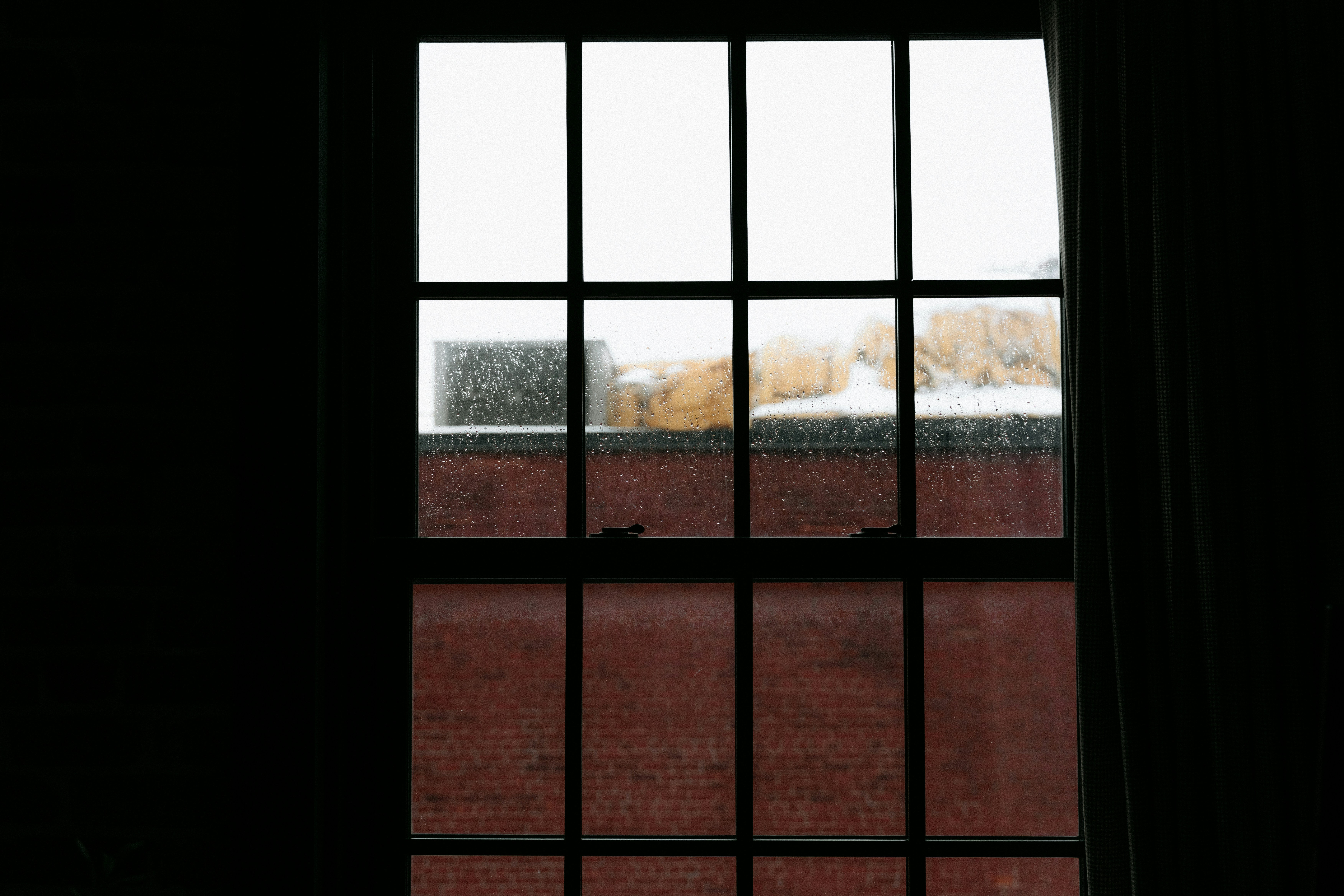Rain-Streaked Window Over a Rooftop: Morning Light Through Grid Framing