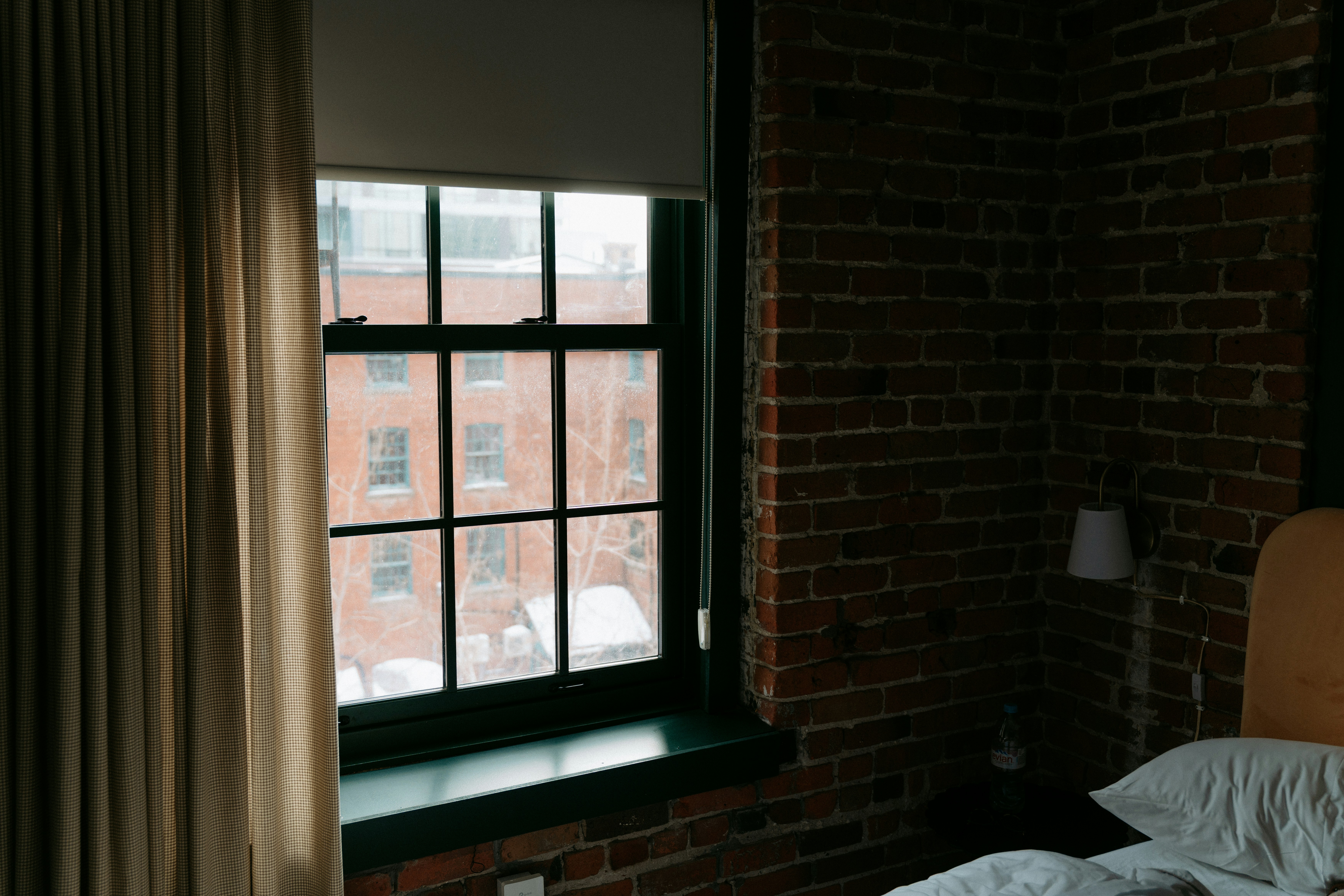 Sunlit Brick Room Framed by Curtains and Window Grid
