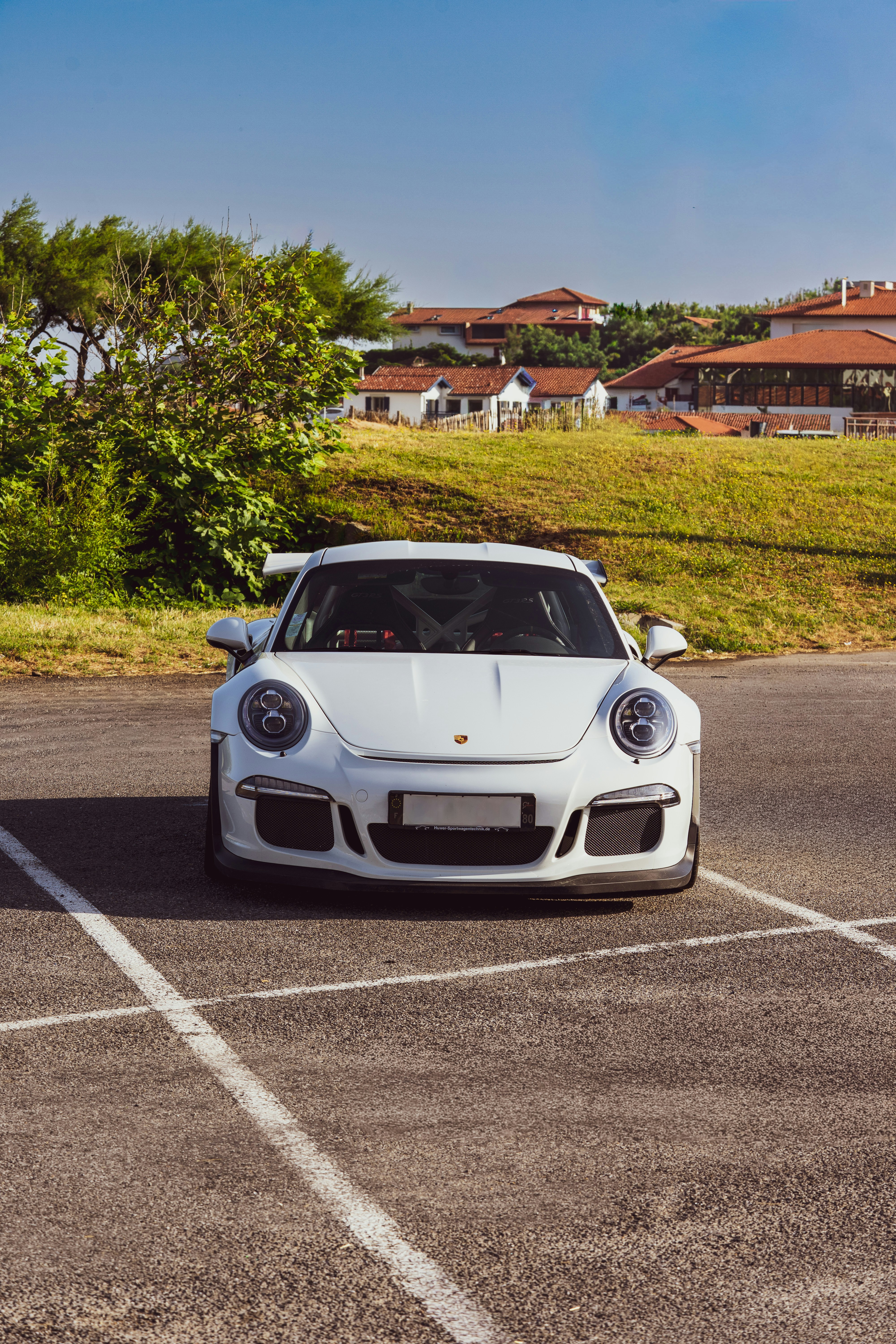 Low-Angle Glance at a White Porsche in a Sunlit Parking Lot