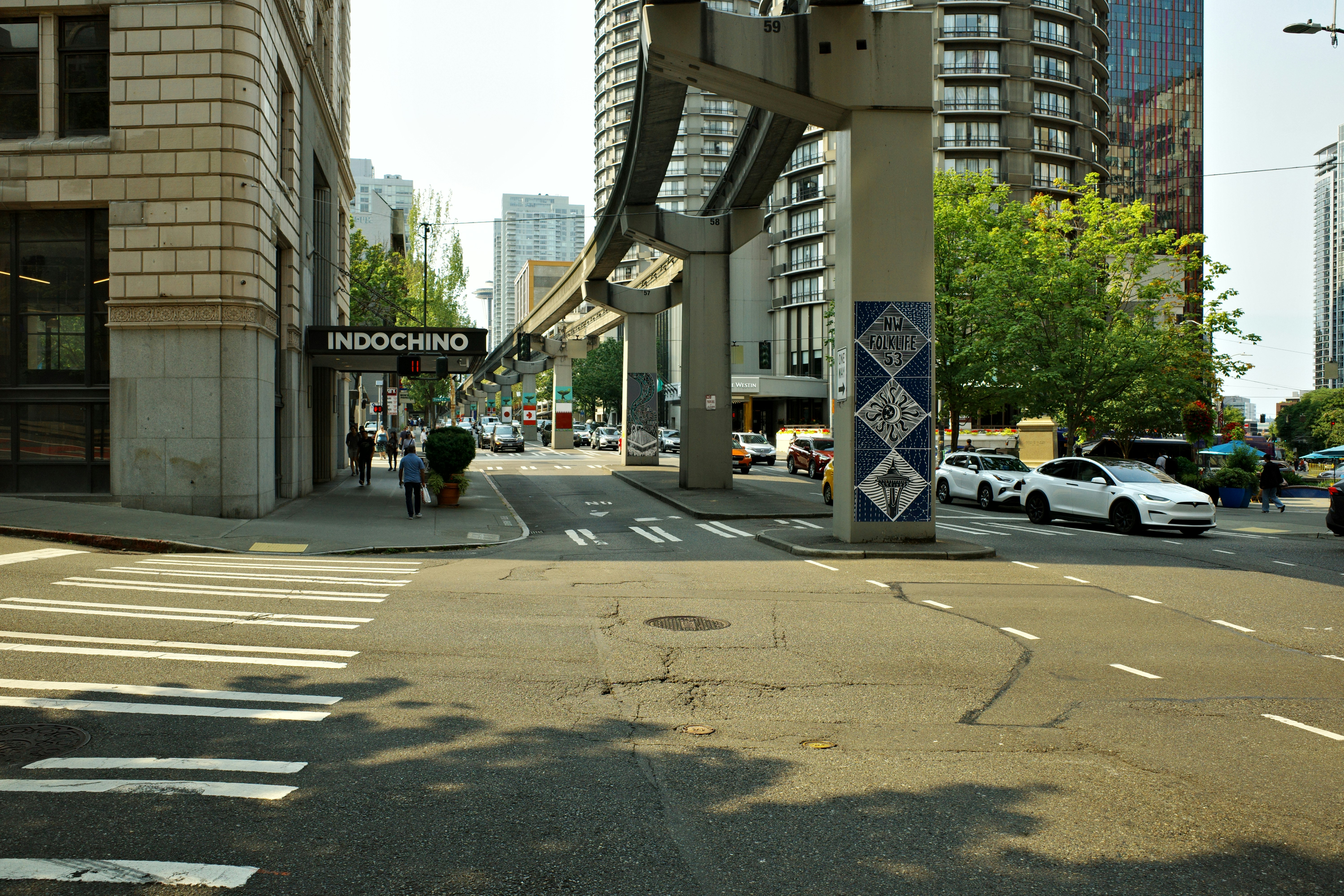 Urban Crossing: Shadowed Street Scene Beneath Elevated Rails