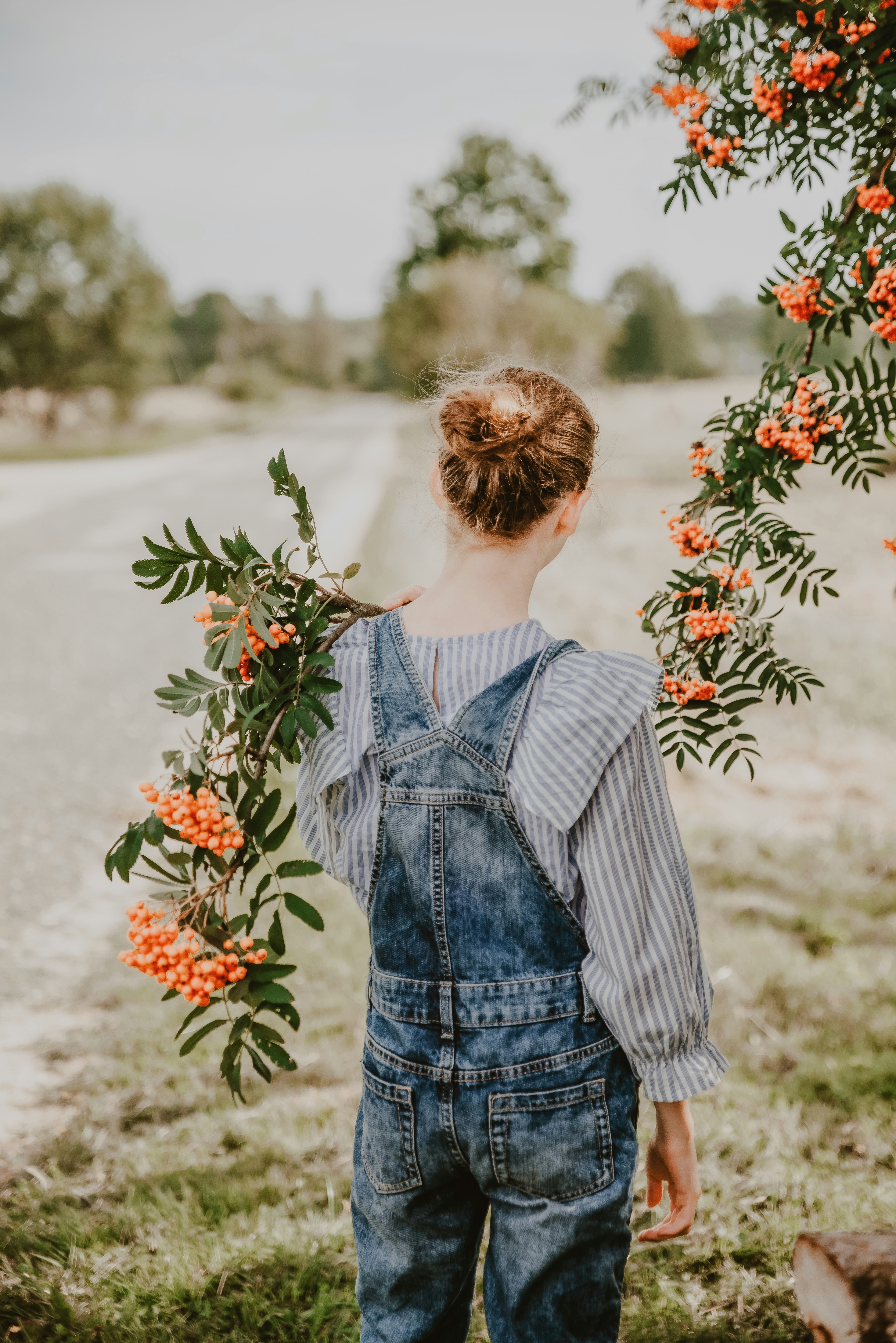 Quiet Portrait: A Girl in Overalls at the Edge of a Flowering Arch