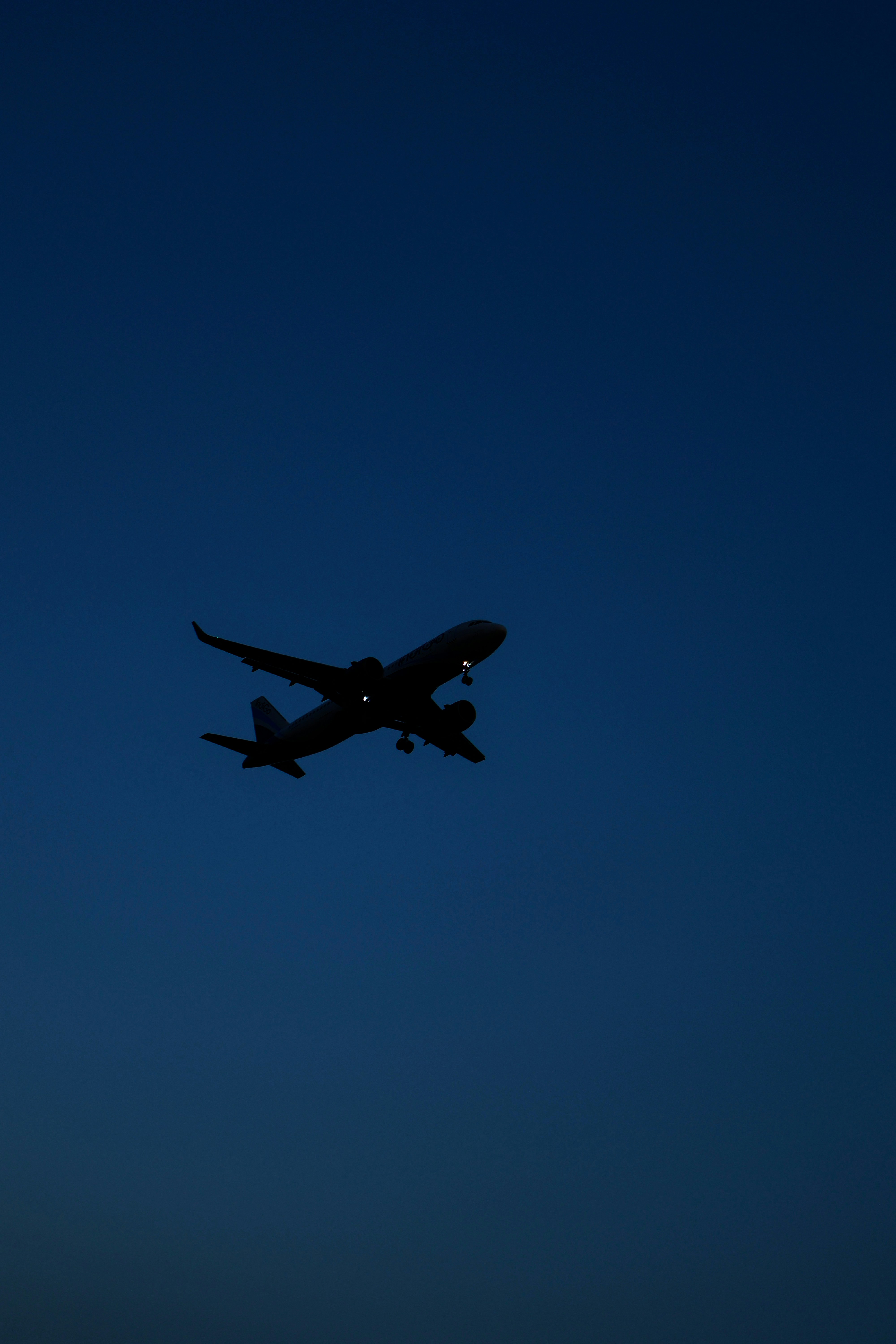 Night descent: silhouette of a passenger jet crossing a dusky sky