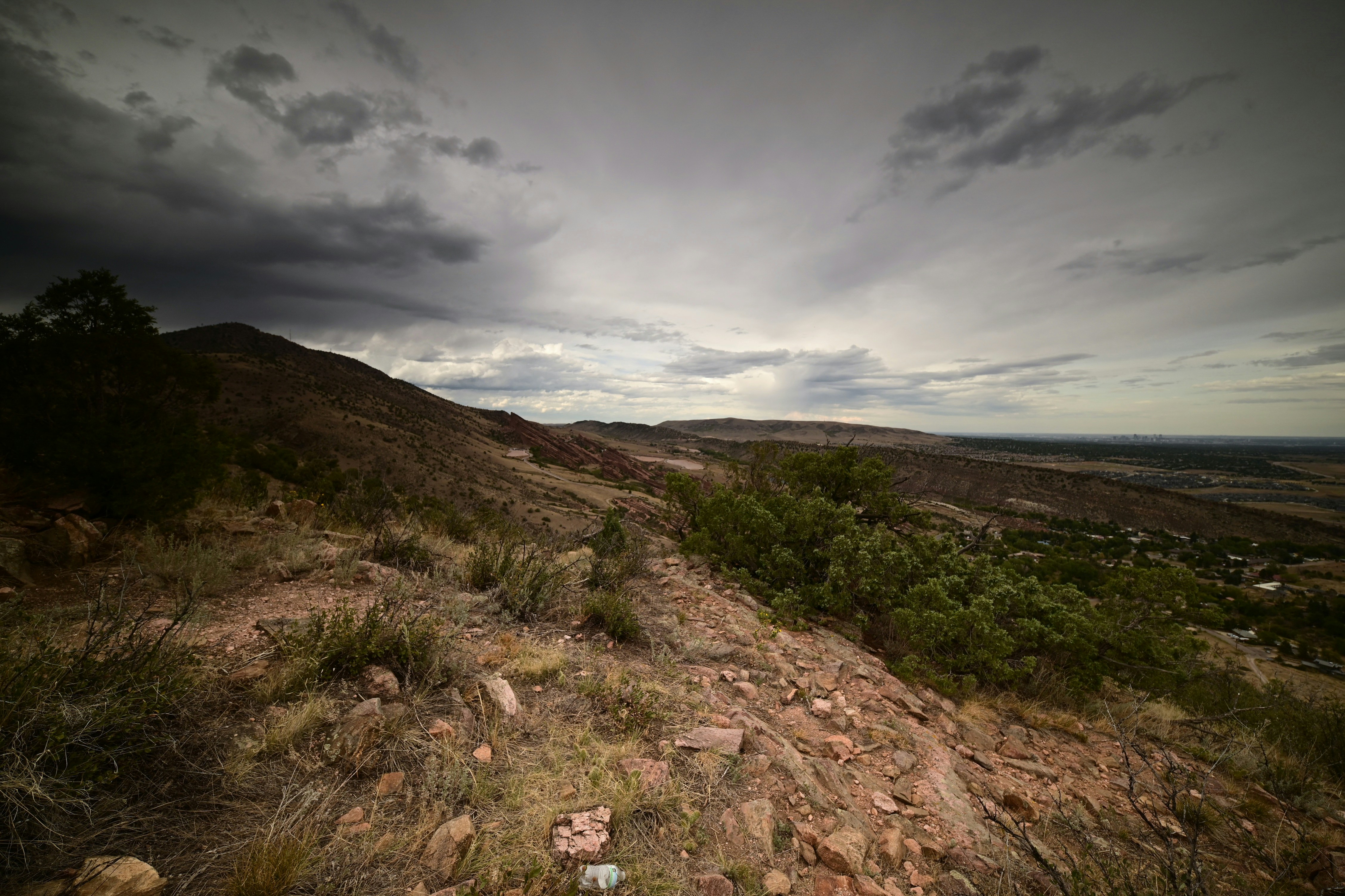 Sunlit ridge overlooking a rugged canyon under sweeping cloudy skies