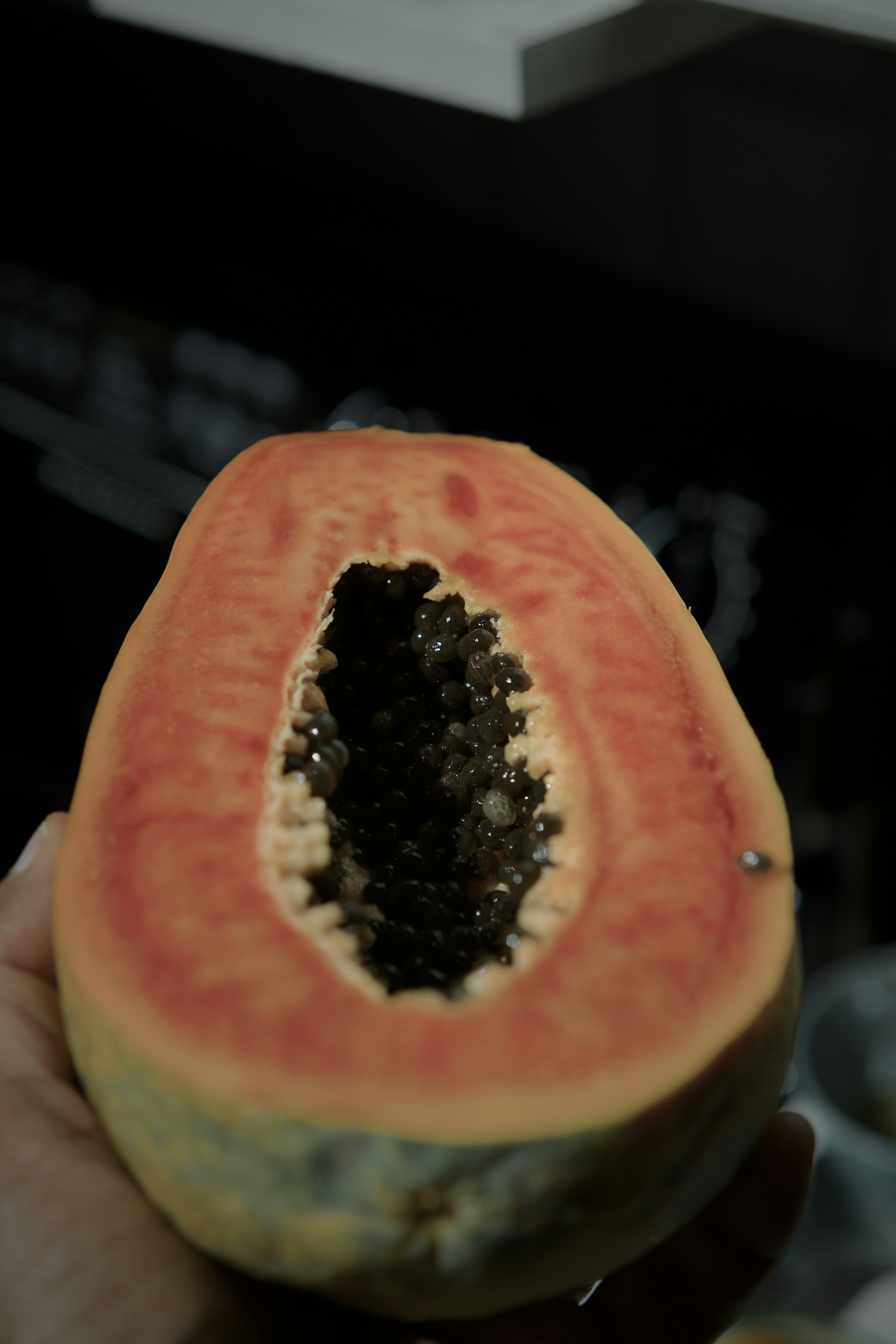 Handheld Halved: A ripe papaya cradled in dim kitchen light
