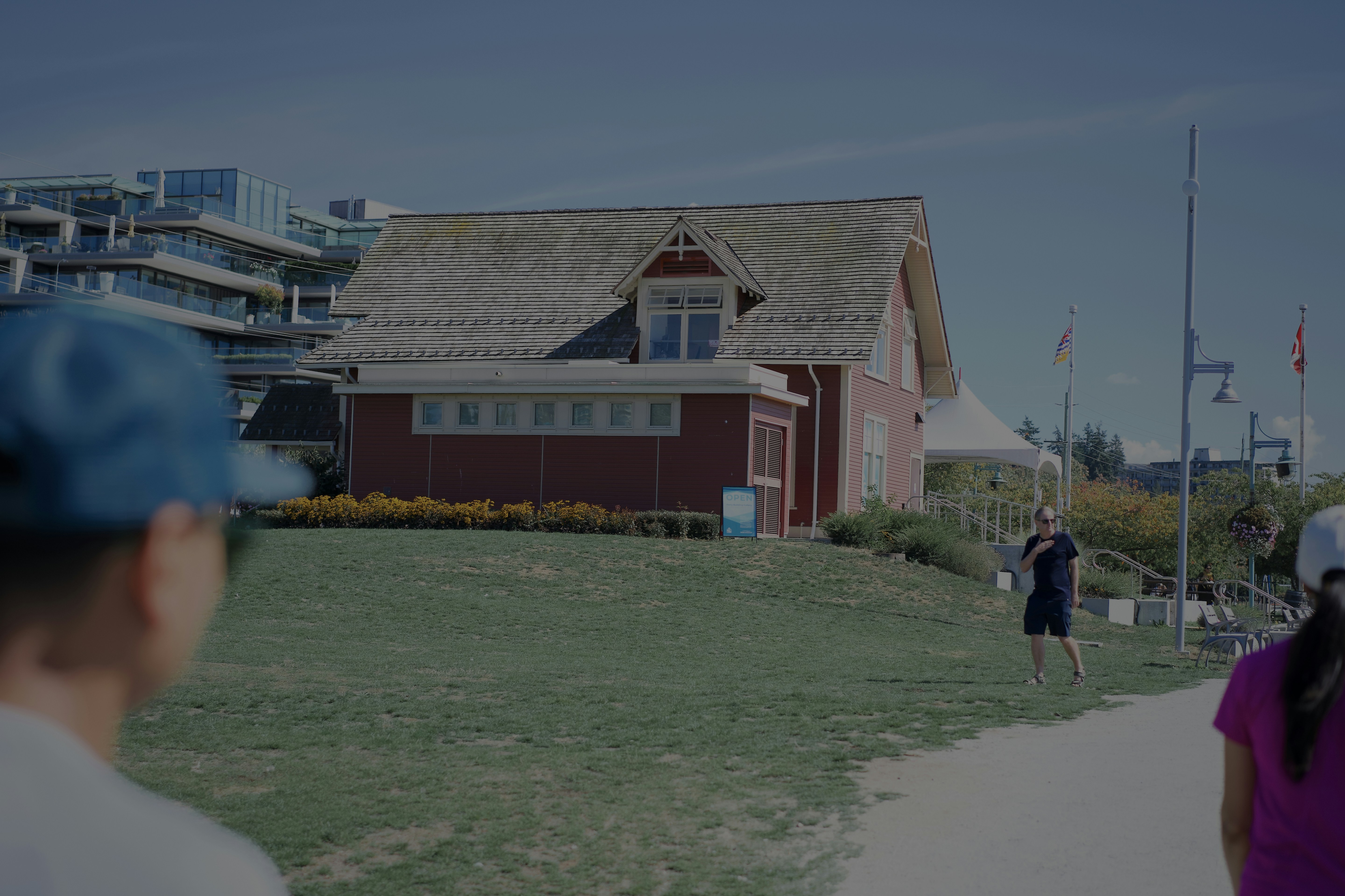 Lone Runner Approaches a Red Coastal Building Across a Sunlit Park