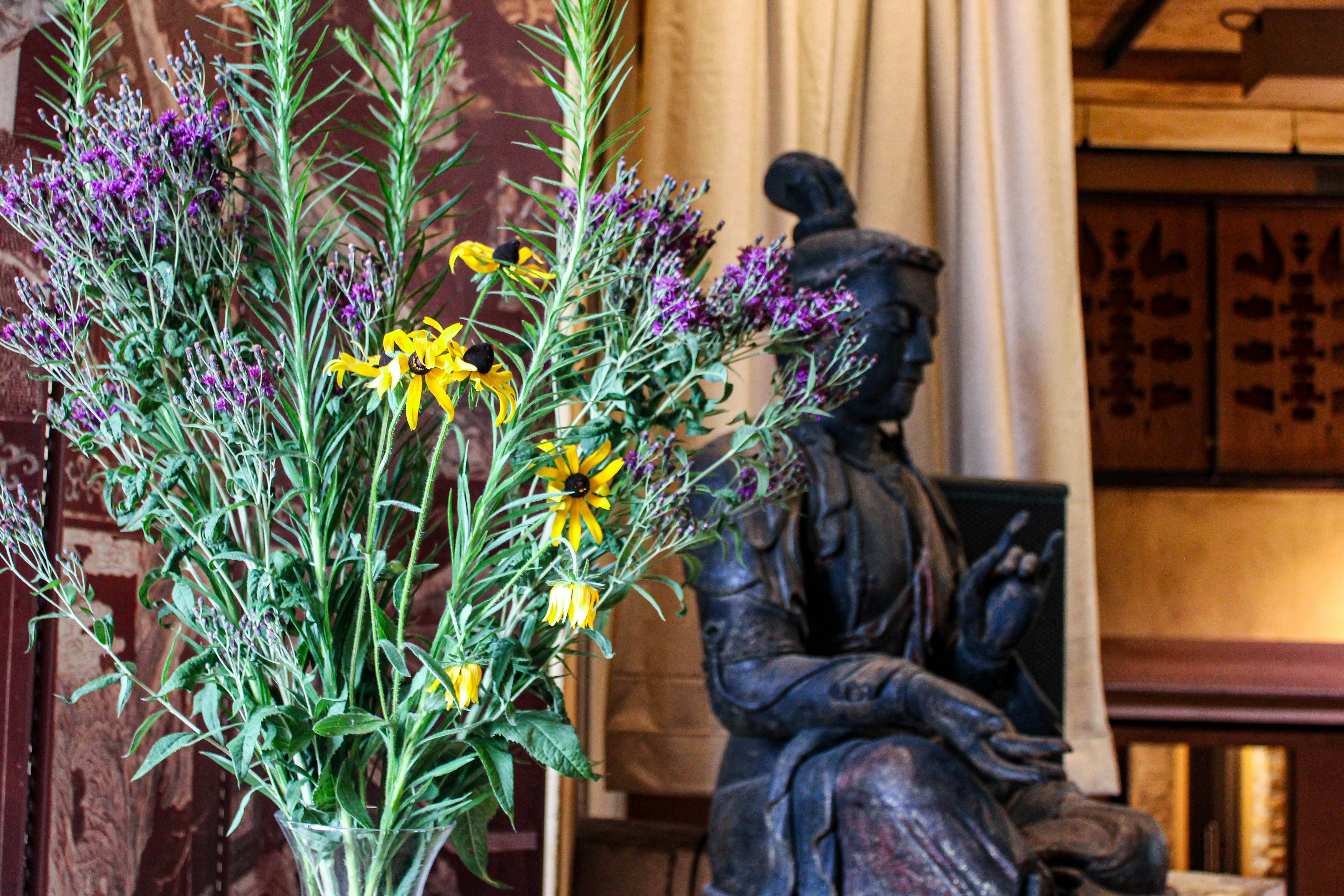 Vivid bouquet in front of a seated statue setting a quiet interior moment