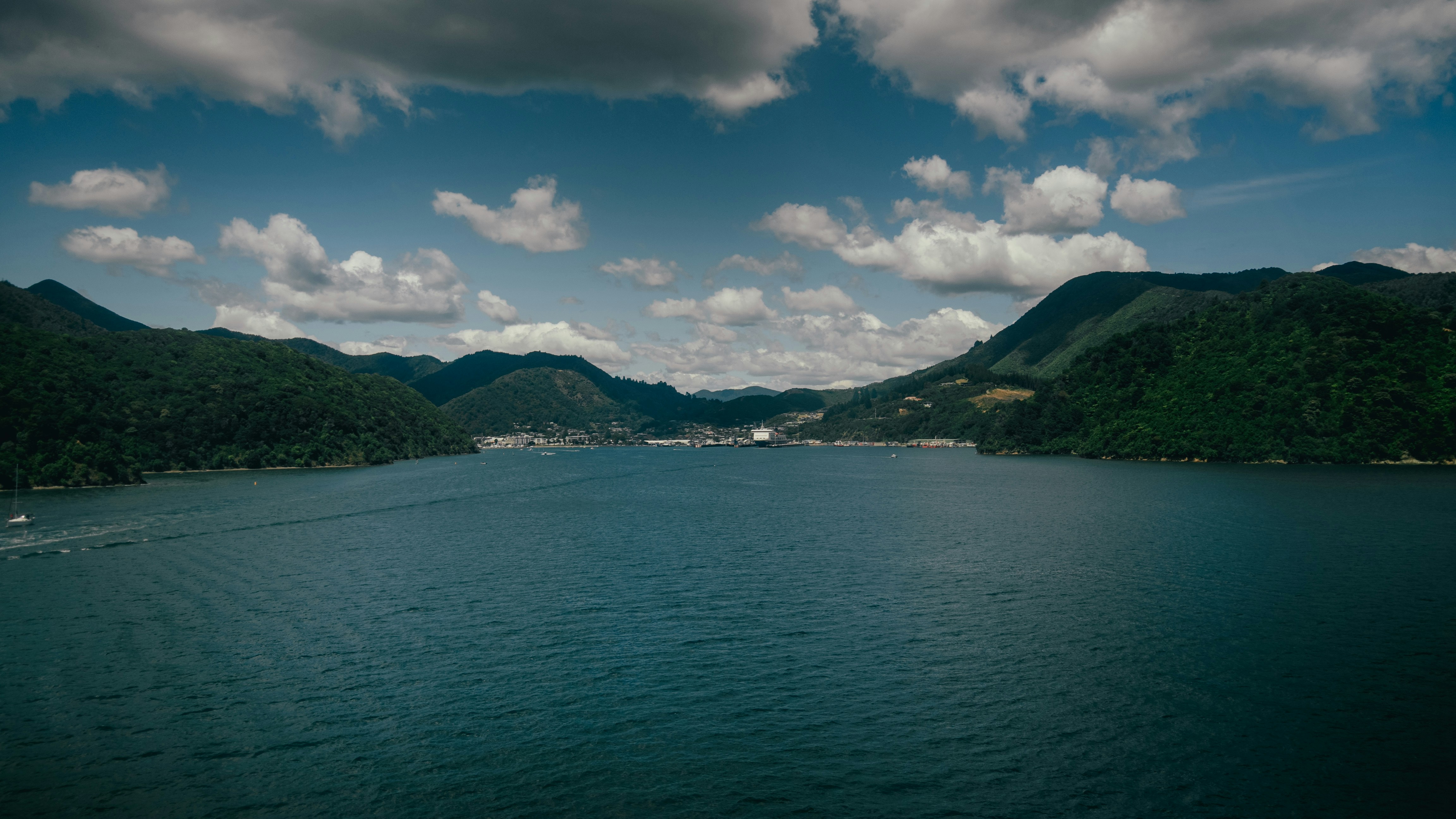 Harbor Between Green Ridges Under a Cloud-Swept Sky