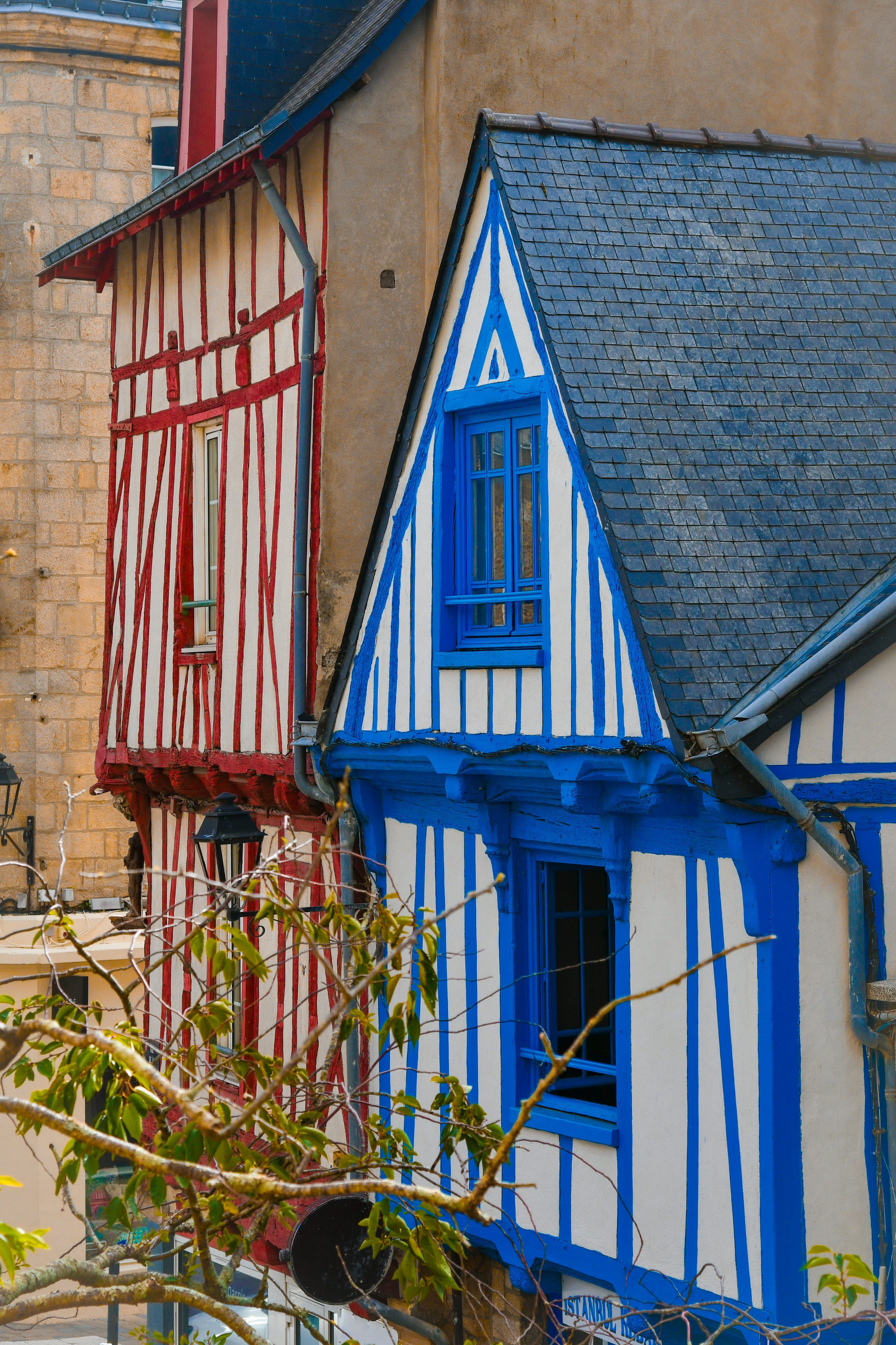 Blue timbered cottage among warm-faced facades