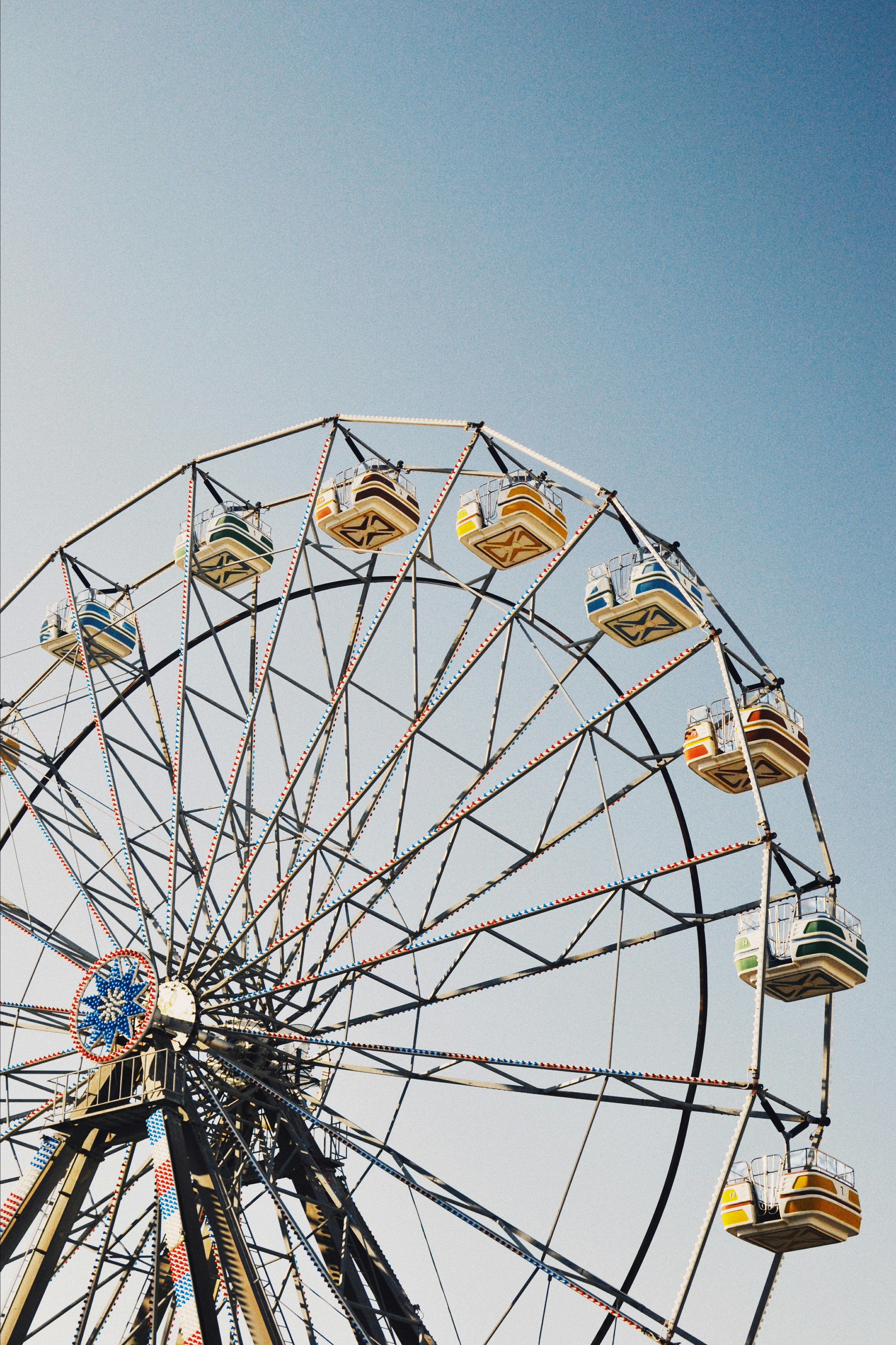 Spin of Colorful Cars: A Ferris Wheel Against a Clear Sky