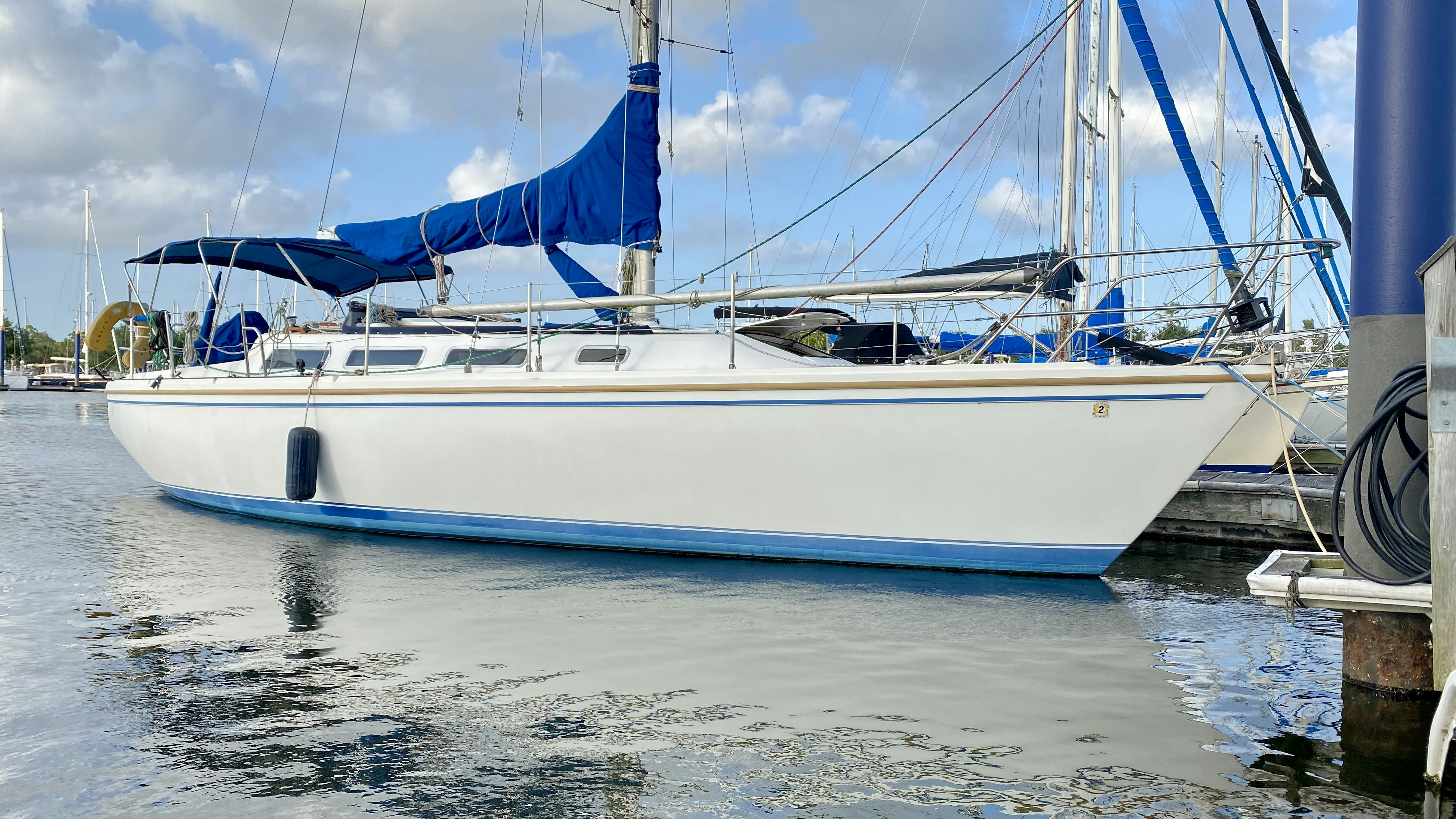 Sailboat at the Marina: White Hull and Blue Sail Cover Resting by the Dock
