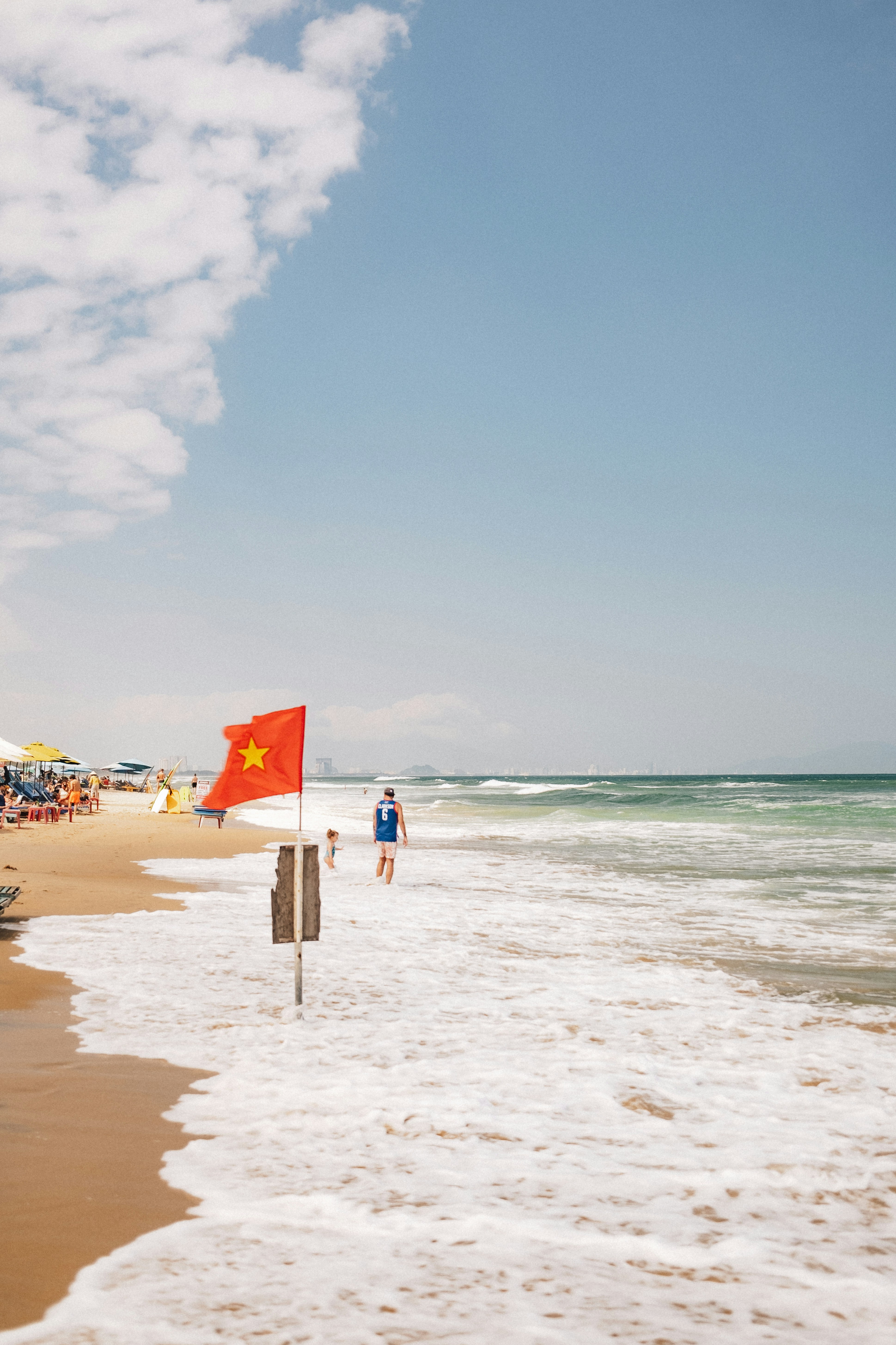 Flag on the shore: a quiet moment near the breaking waves