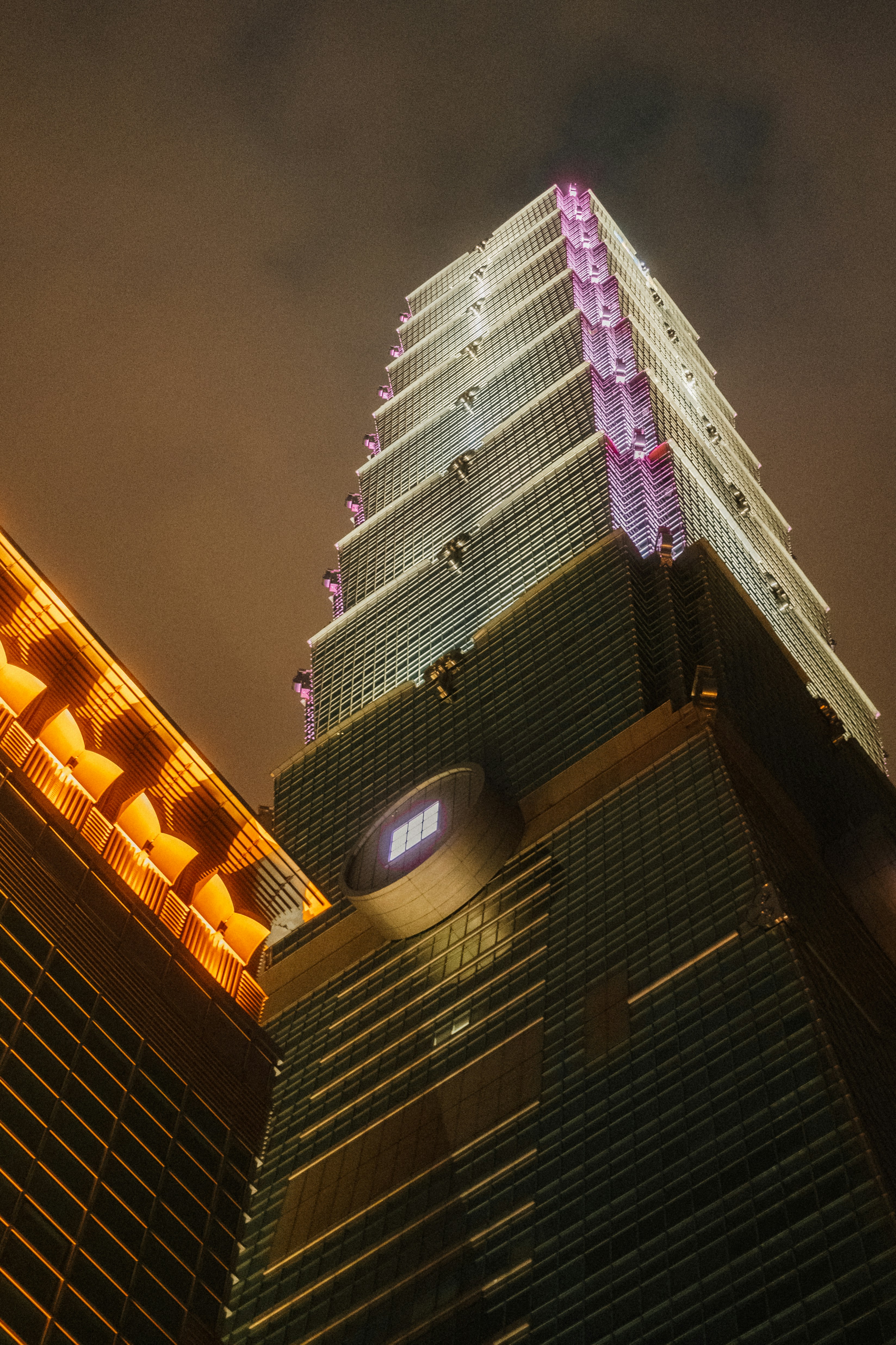 Night ascent: a neon-lit tower reaching into cloudy skies