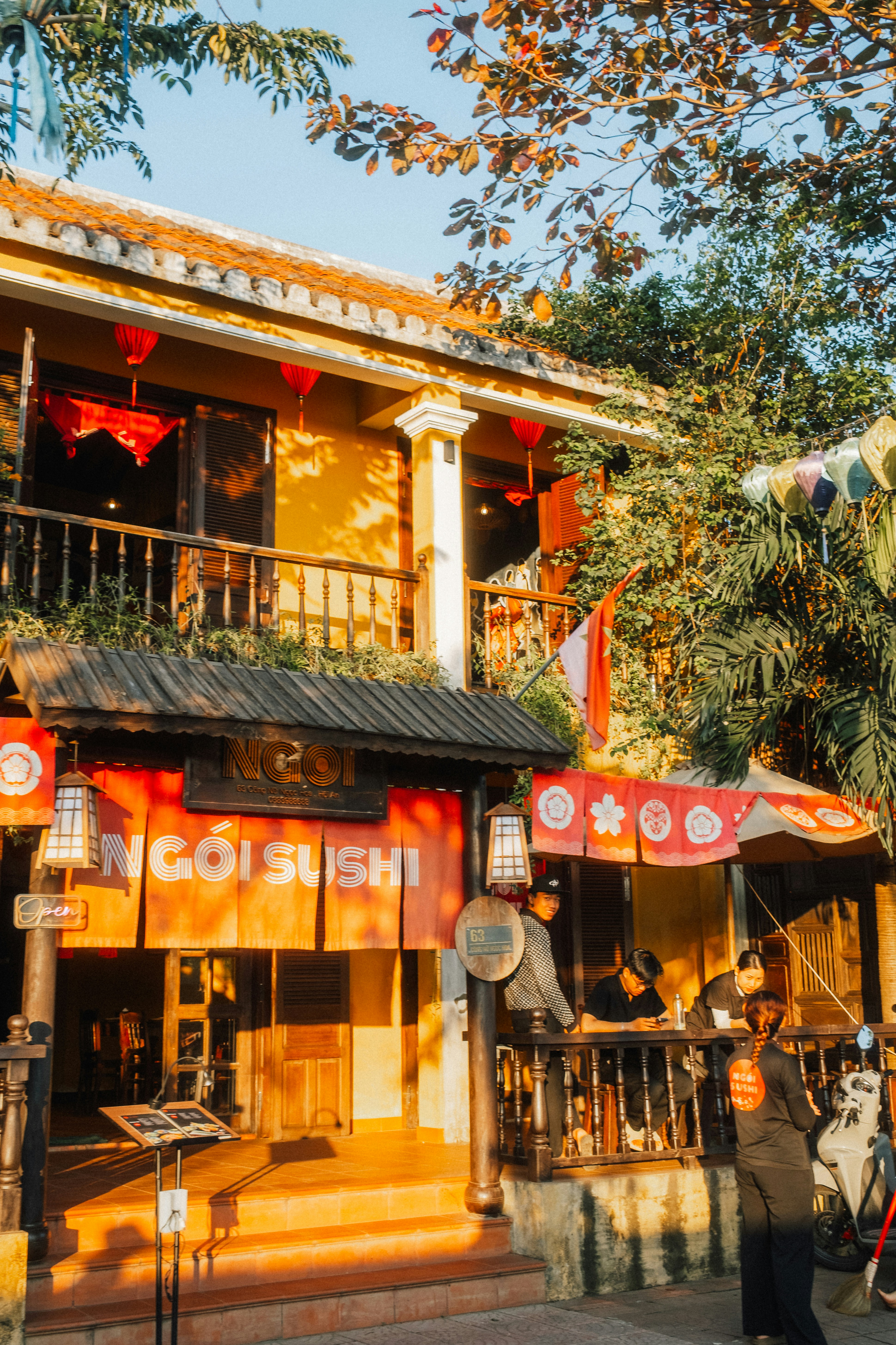 Warm storefront bustle under a sunlit balcony