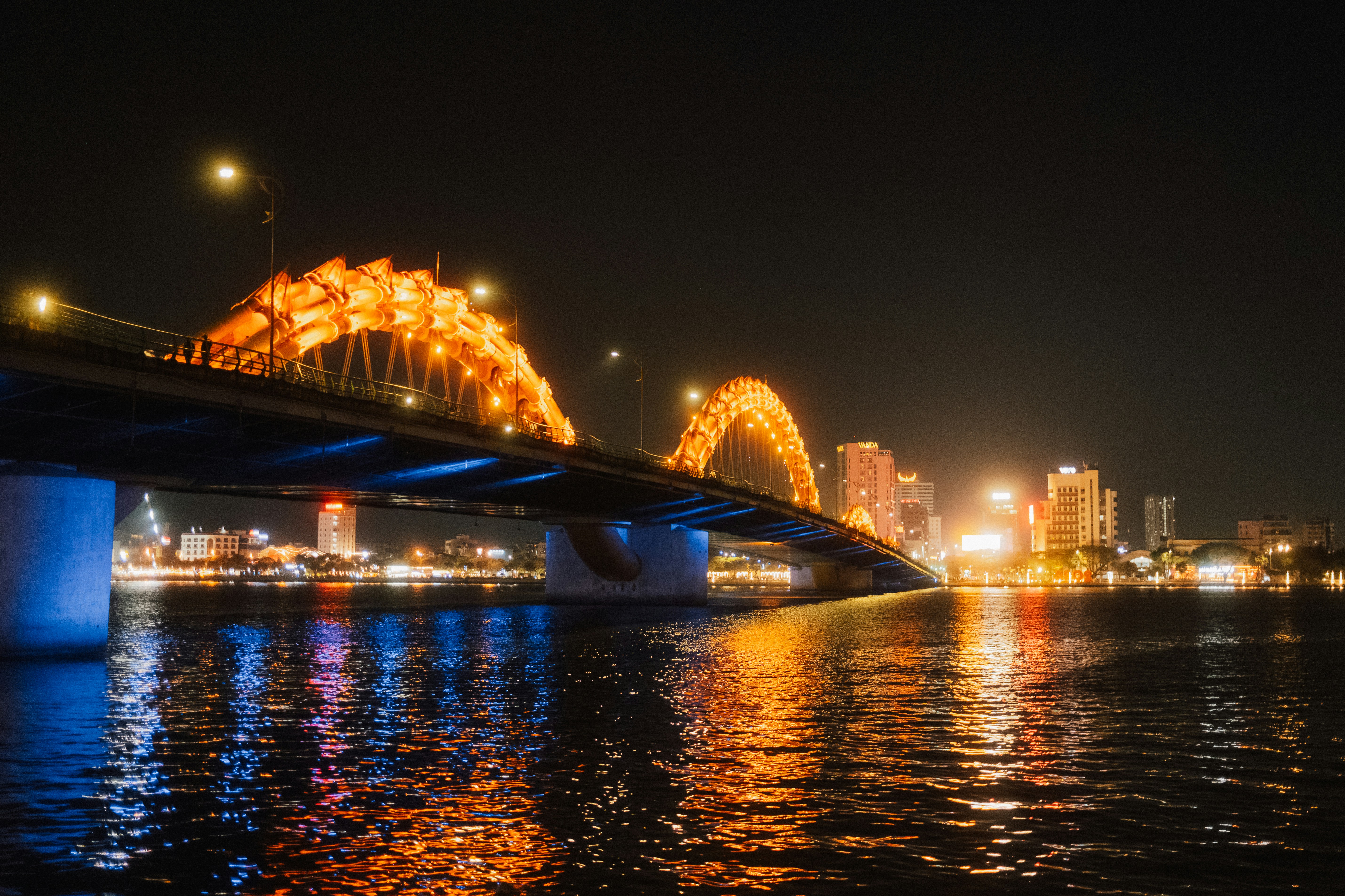 Neon Arc over Quiet Water: Night Scene at a Lit City Bridge