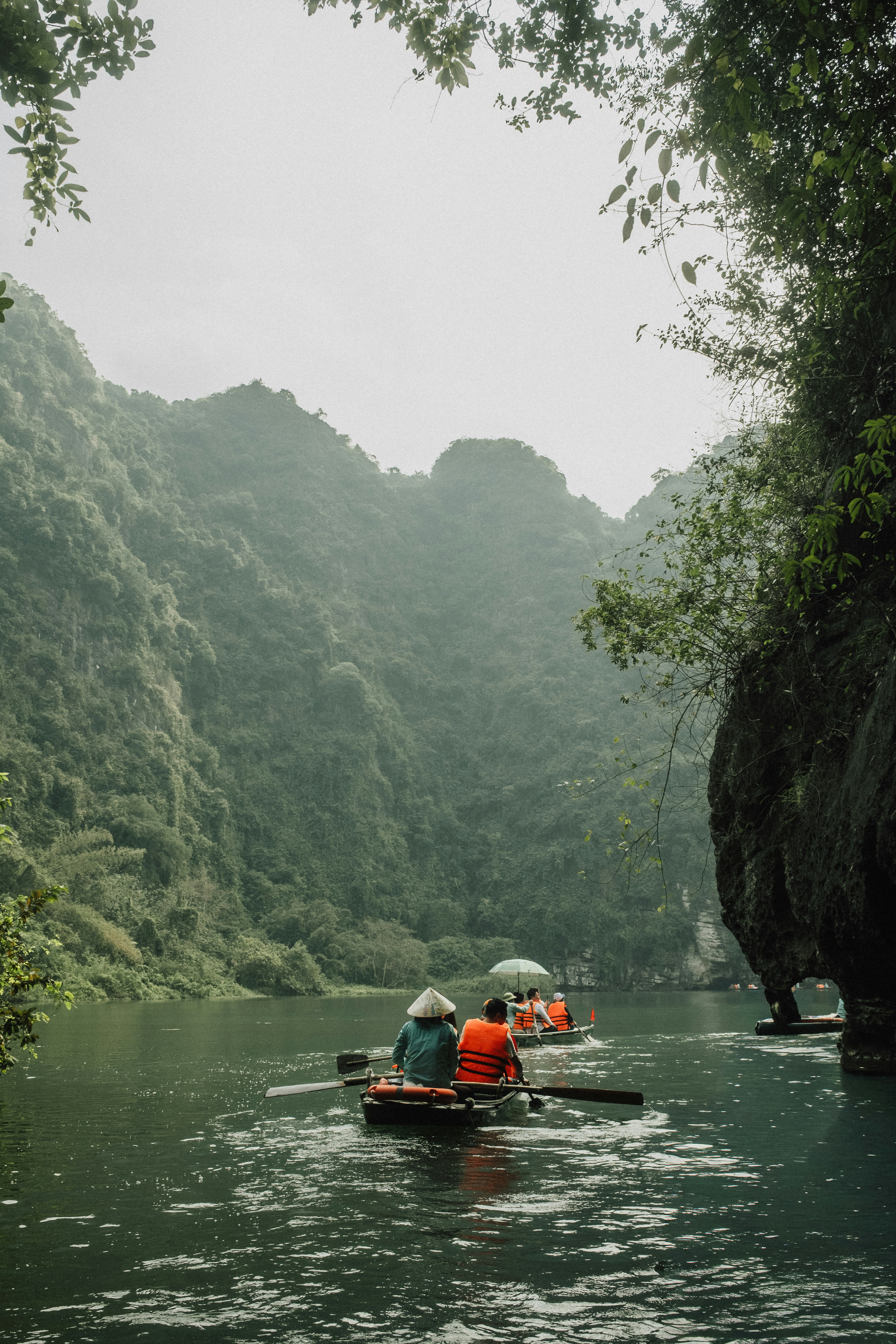 Rowboats drifting through a misted limestone canyon