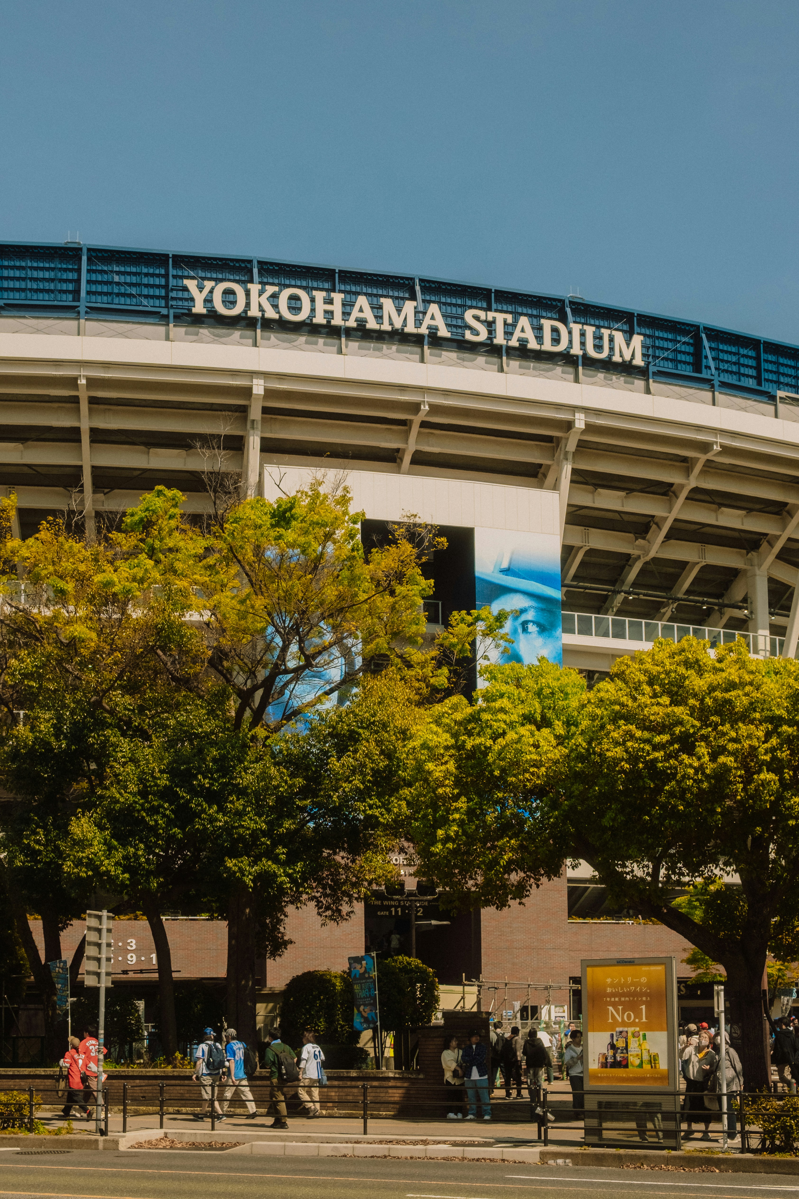 Yokohama Stadium Facade: Trees, Signage, and Crowds at Dusk