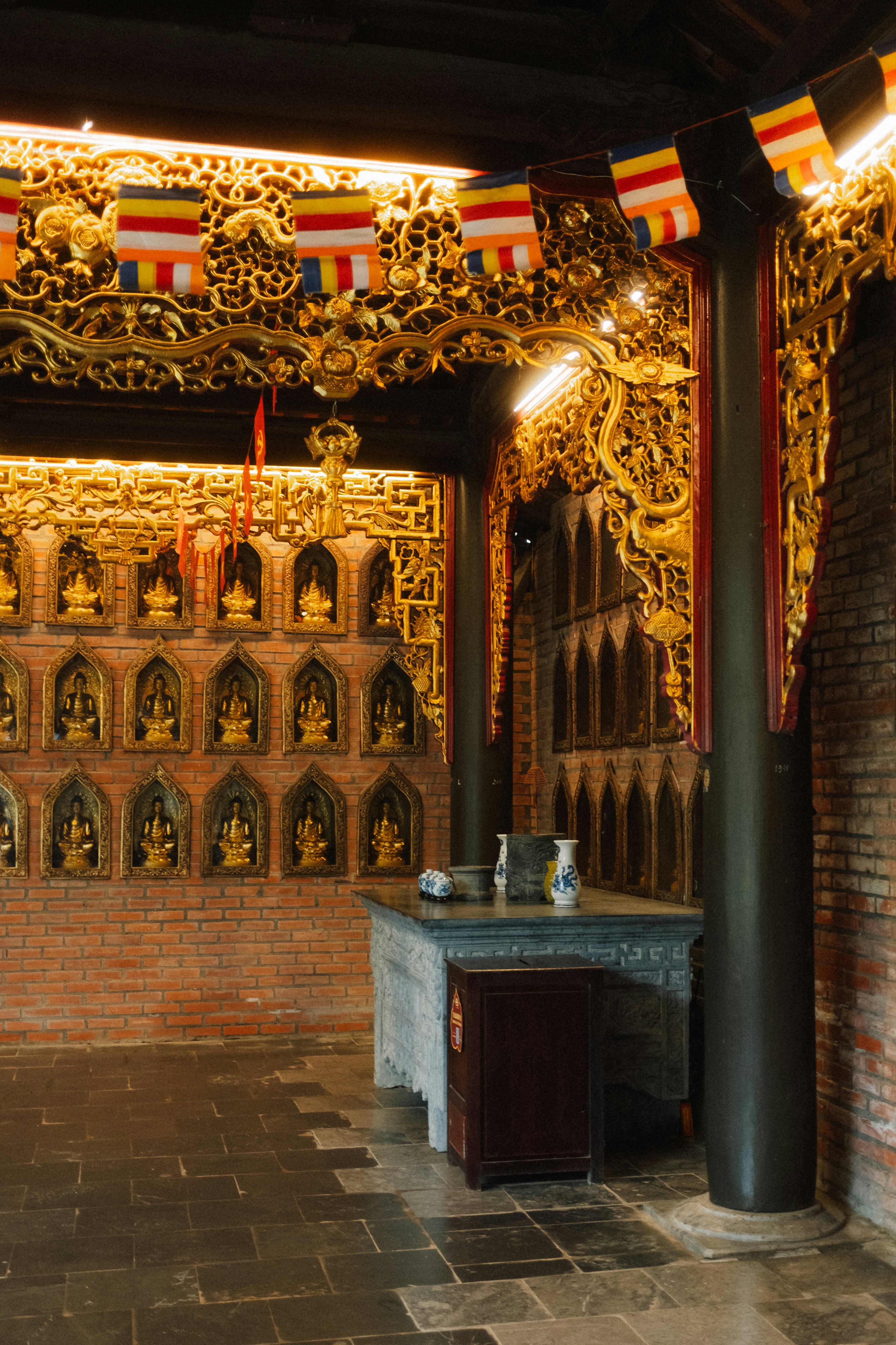 Golden Shrine Frame: Intricate Carvings and Flags in a Serene Temple Interior