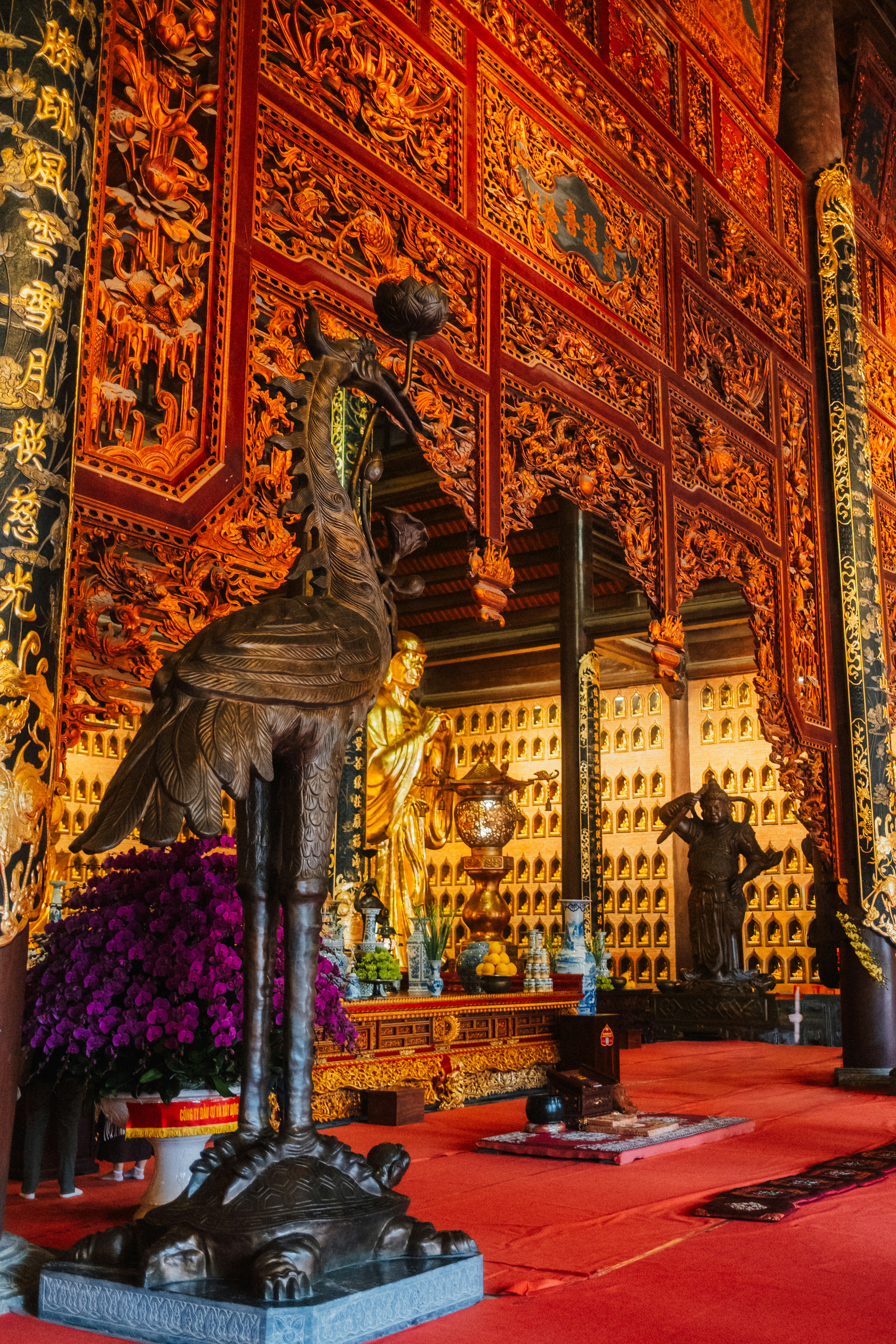 Ornate Shrine of Bronze Figures Under Red Golden Carvings