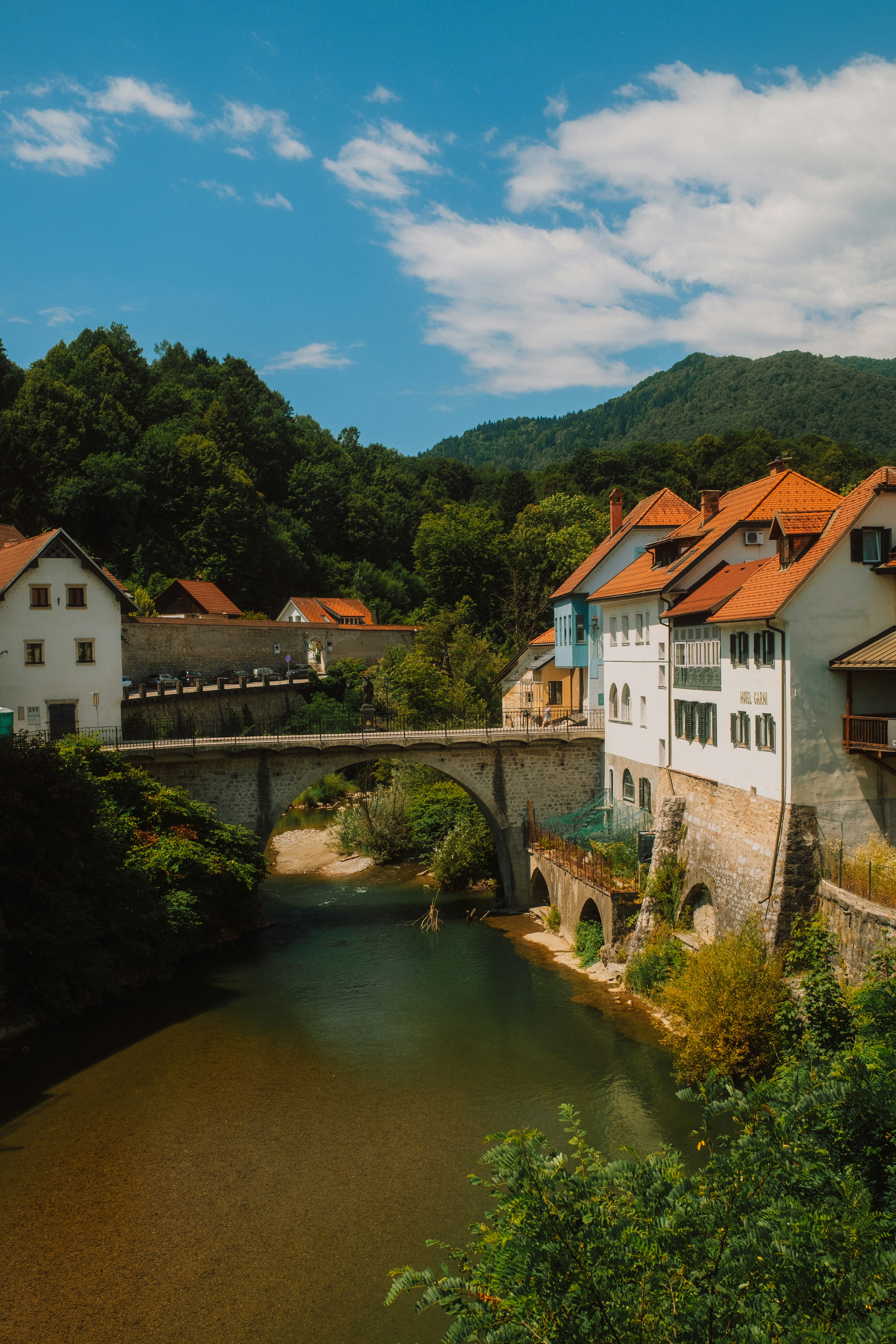 Cantilevered Village Over River: A Sunlit European Bridge Scene