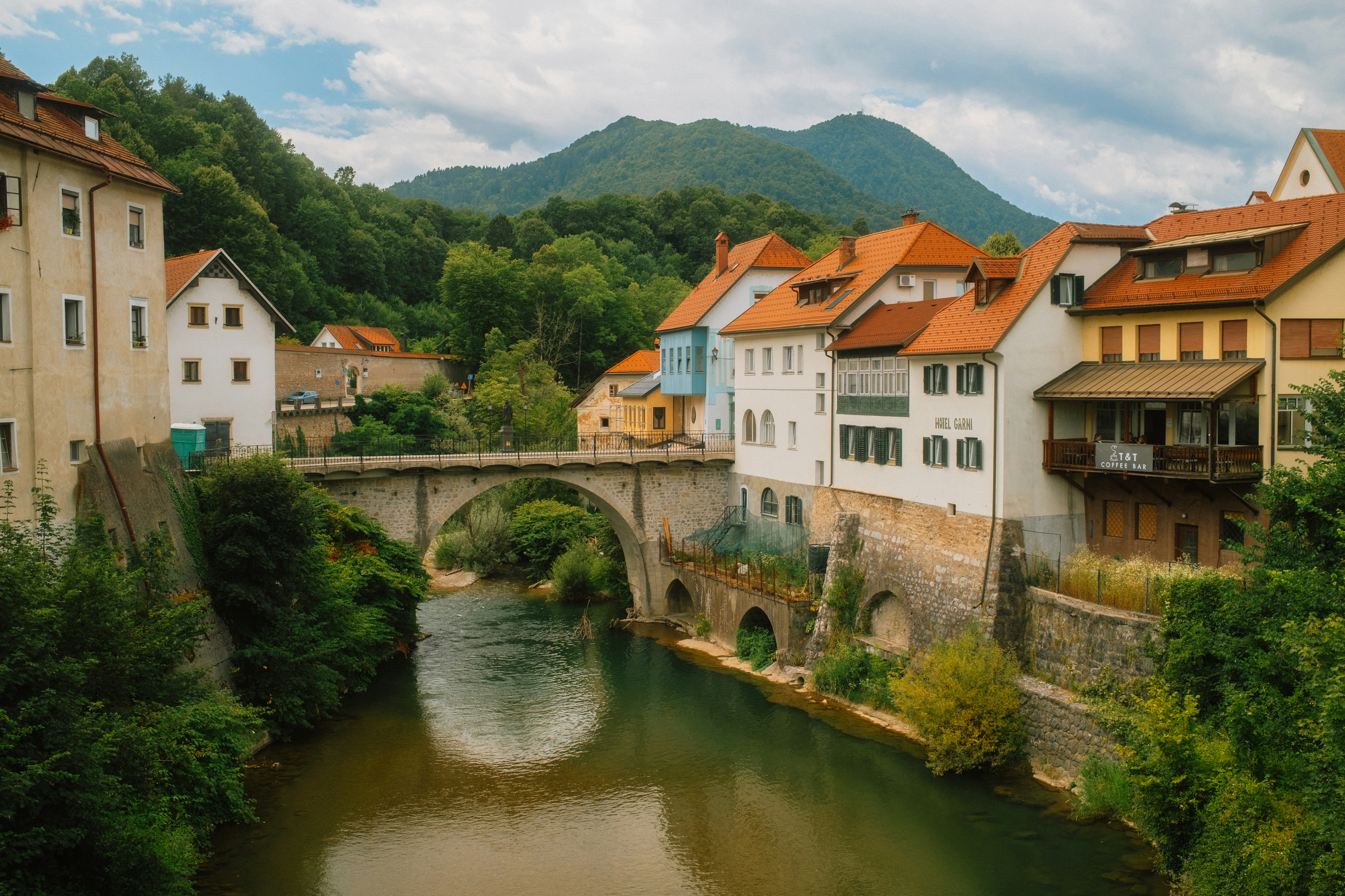 Historic stone bridge and pastel houses over a tranquil river valley