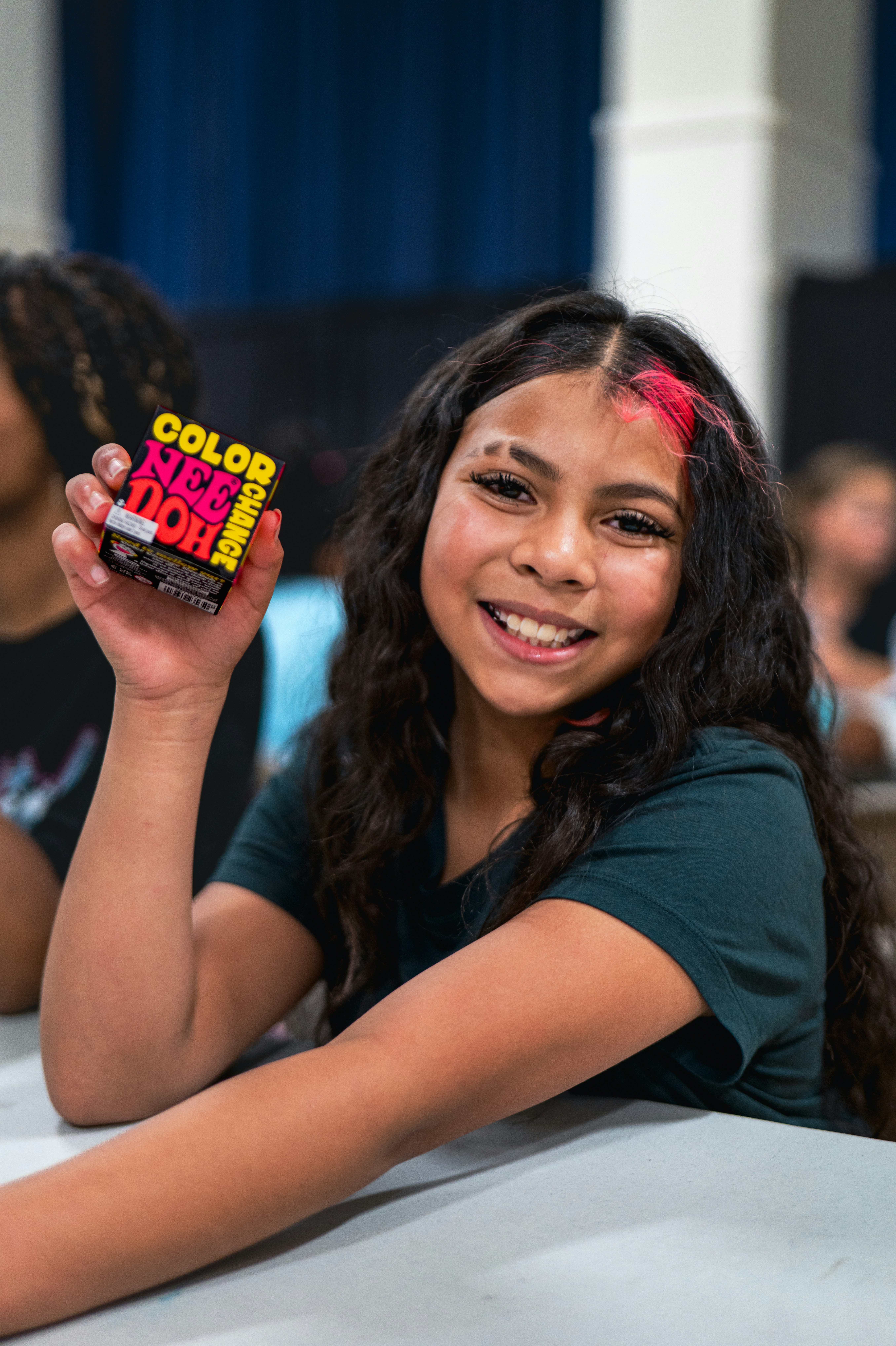 Smiling Reason: A Girl with a Colorful Card at a Table