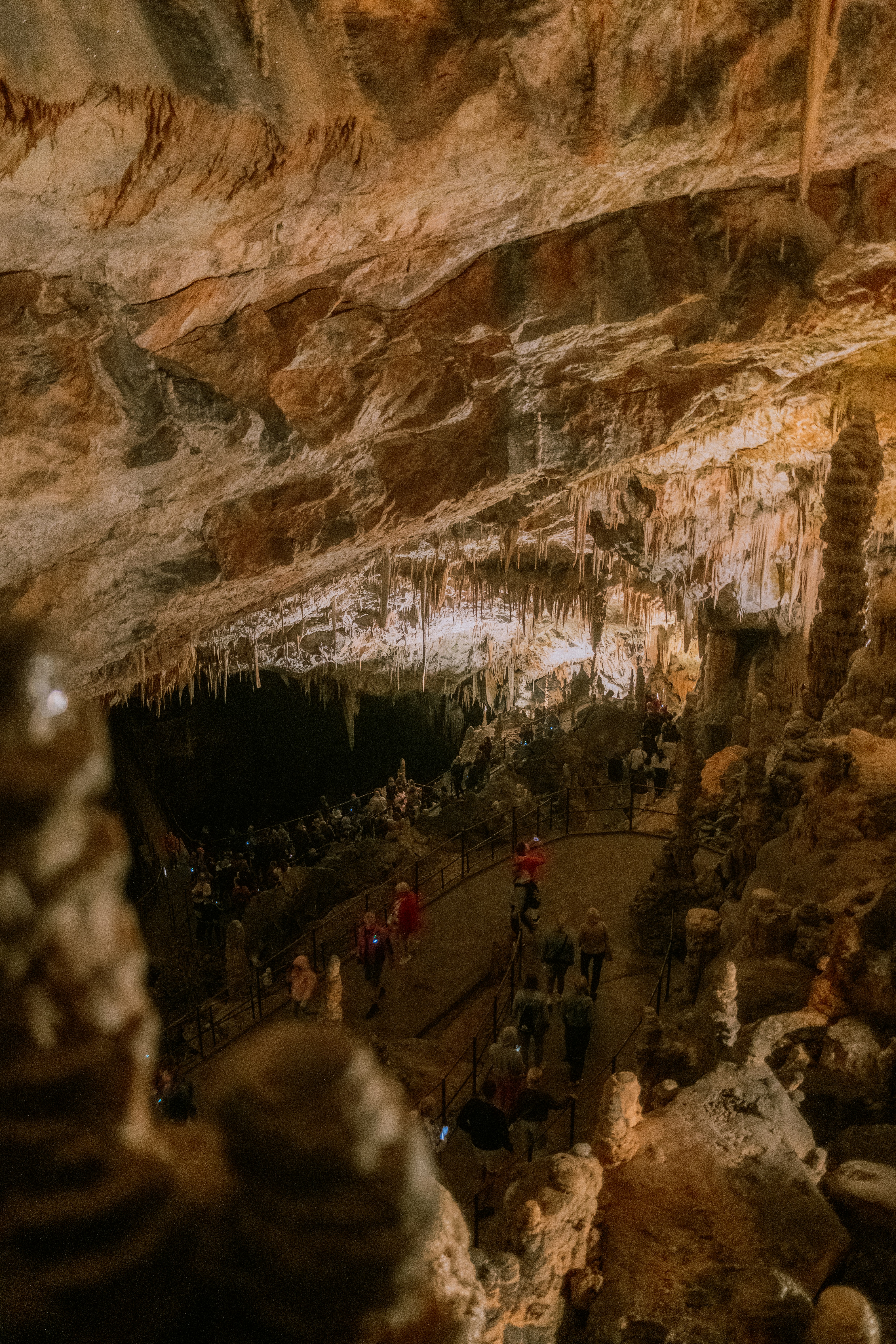 Stalactite Cathedral: Visitors Guiding a Curving Path Through a Cavernous Gallery