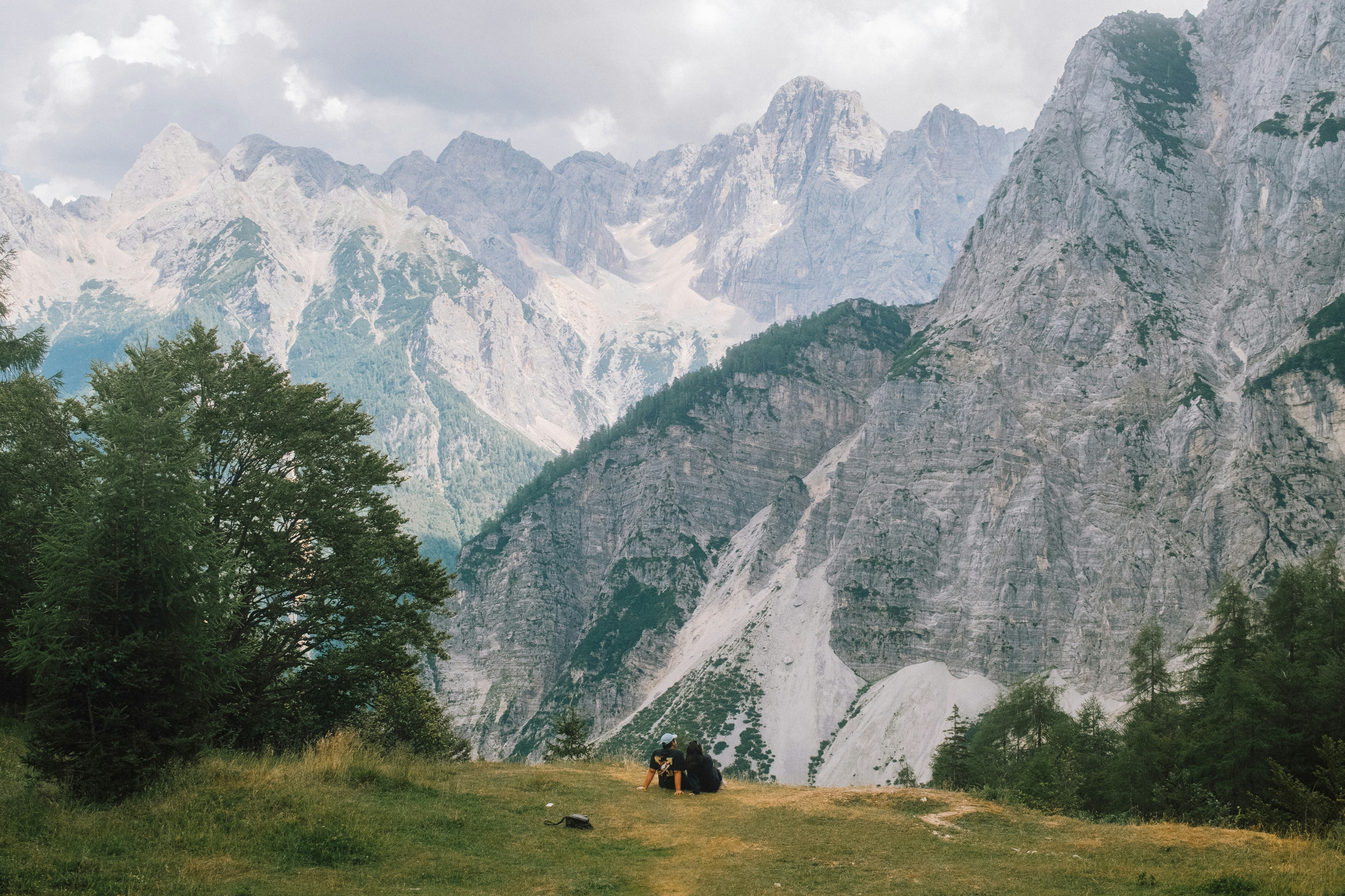 Two hikers at the edge of a alpine meadow with jagged peaks