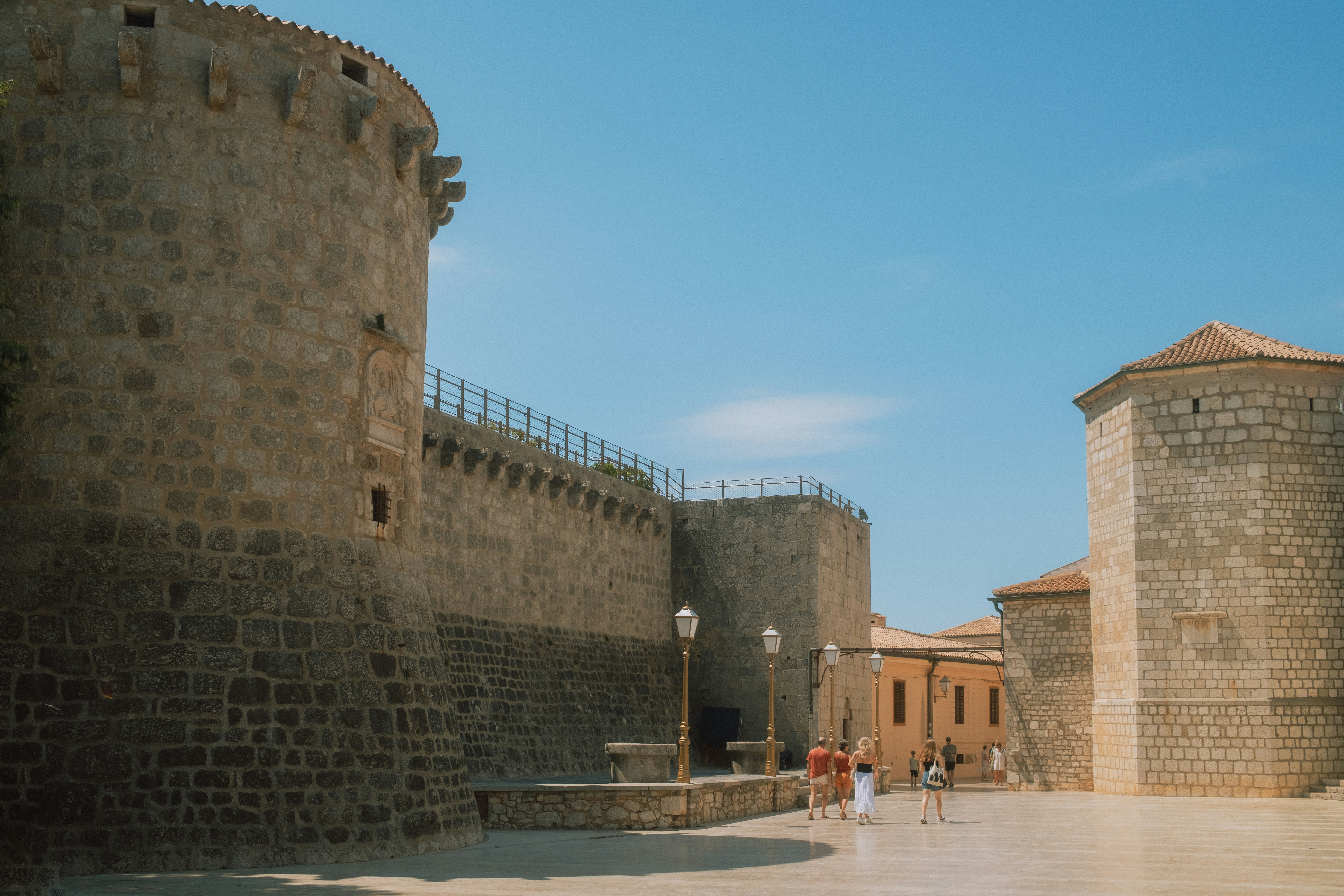 Sunlit Fortress Courtyard: People at the Gate