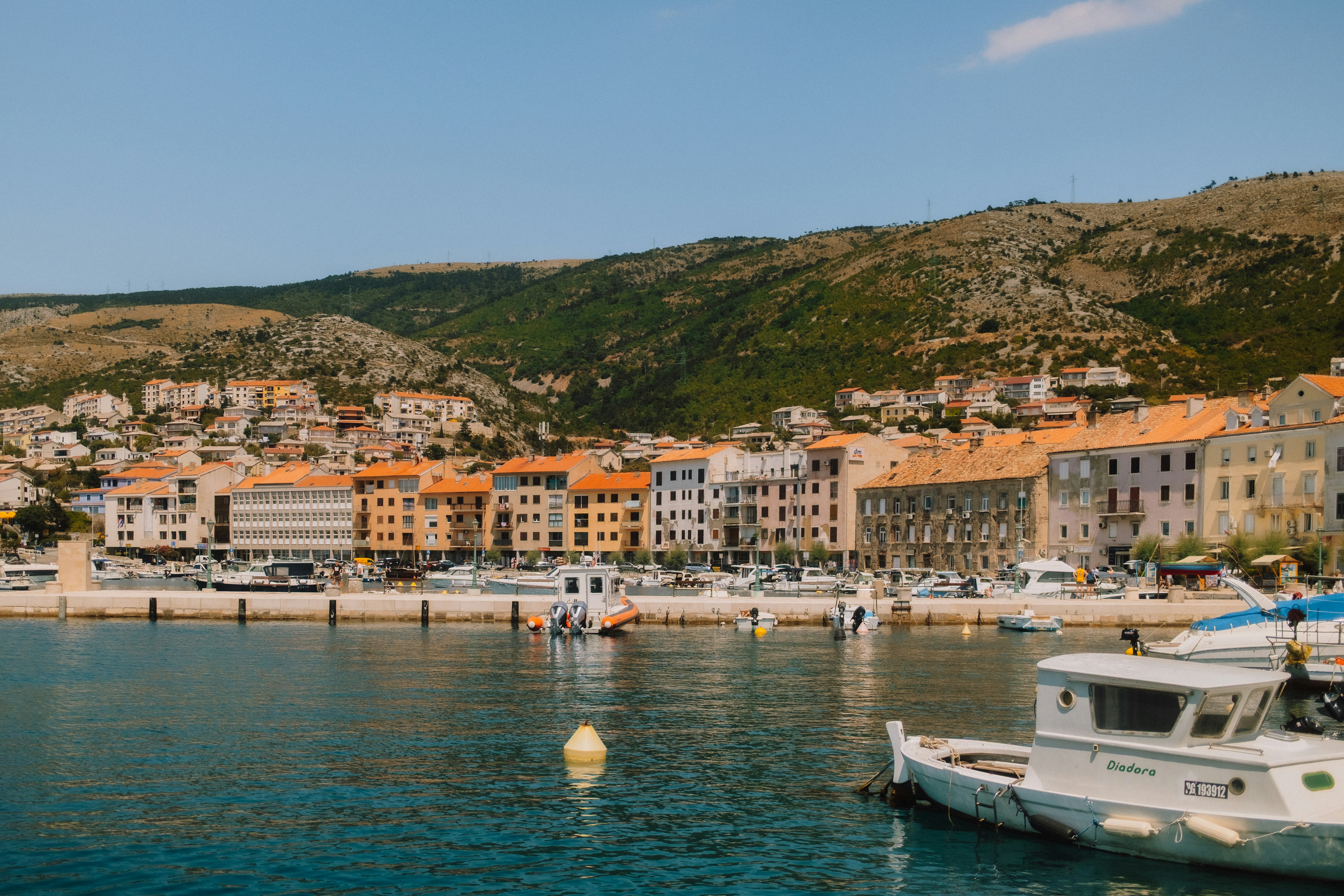 Sunlit harbor echoes: pastel buildings cradle a quiet marina