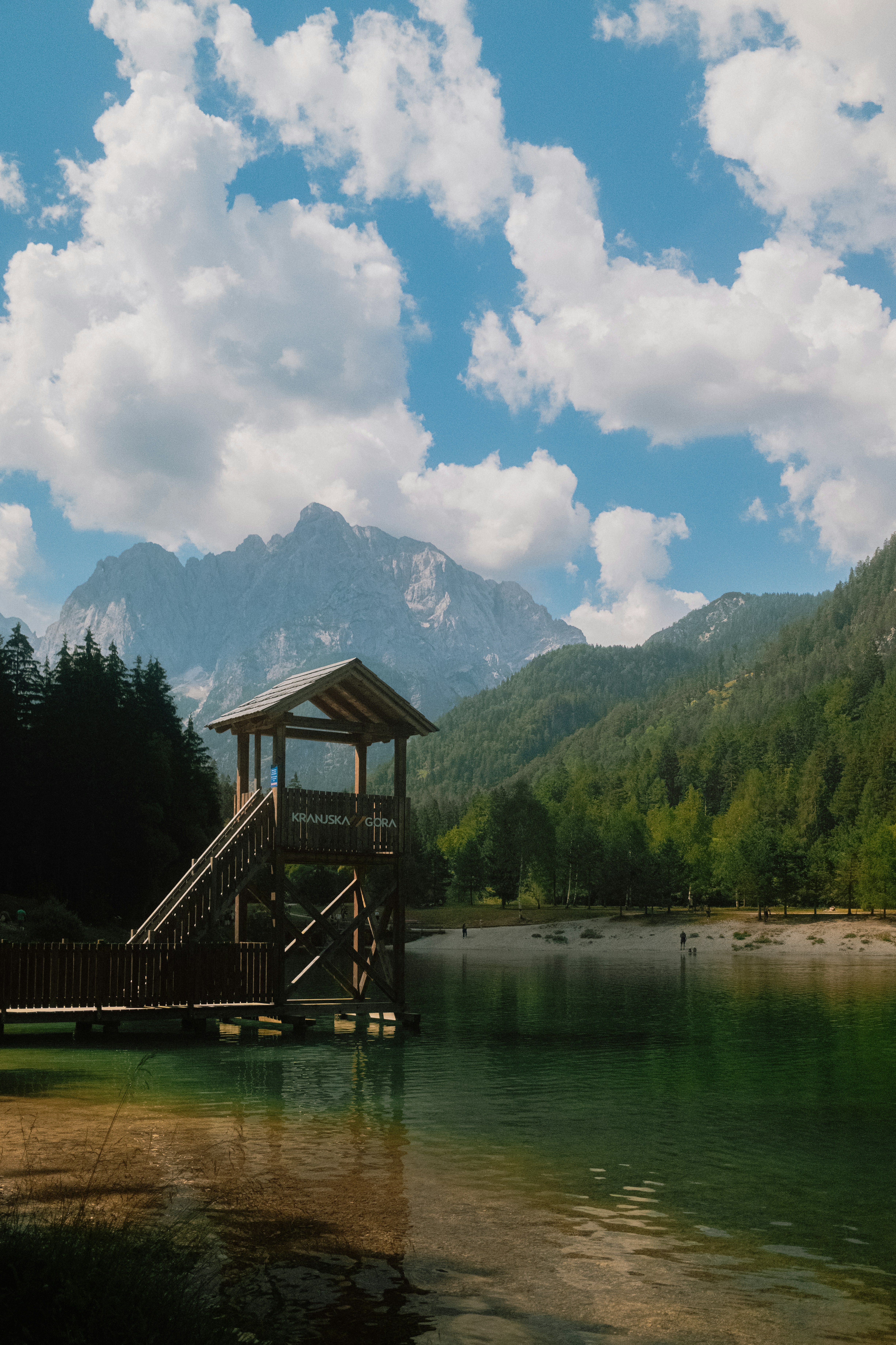 Wooden lifeguard tower by a tranquil alpine lake beneath towering peaks