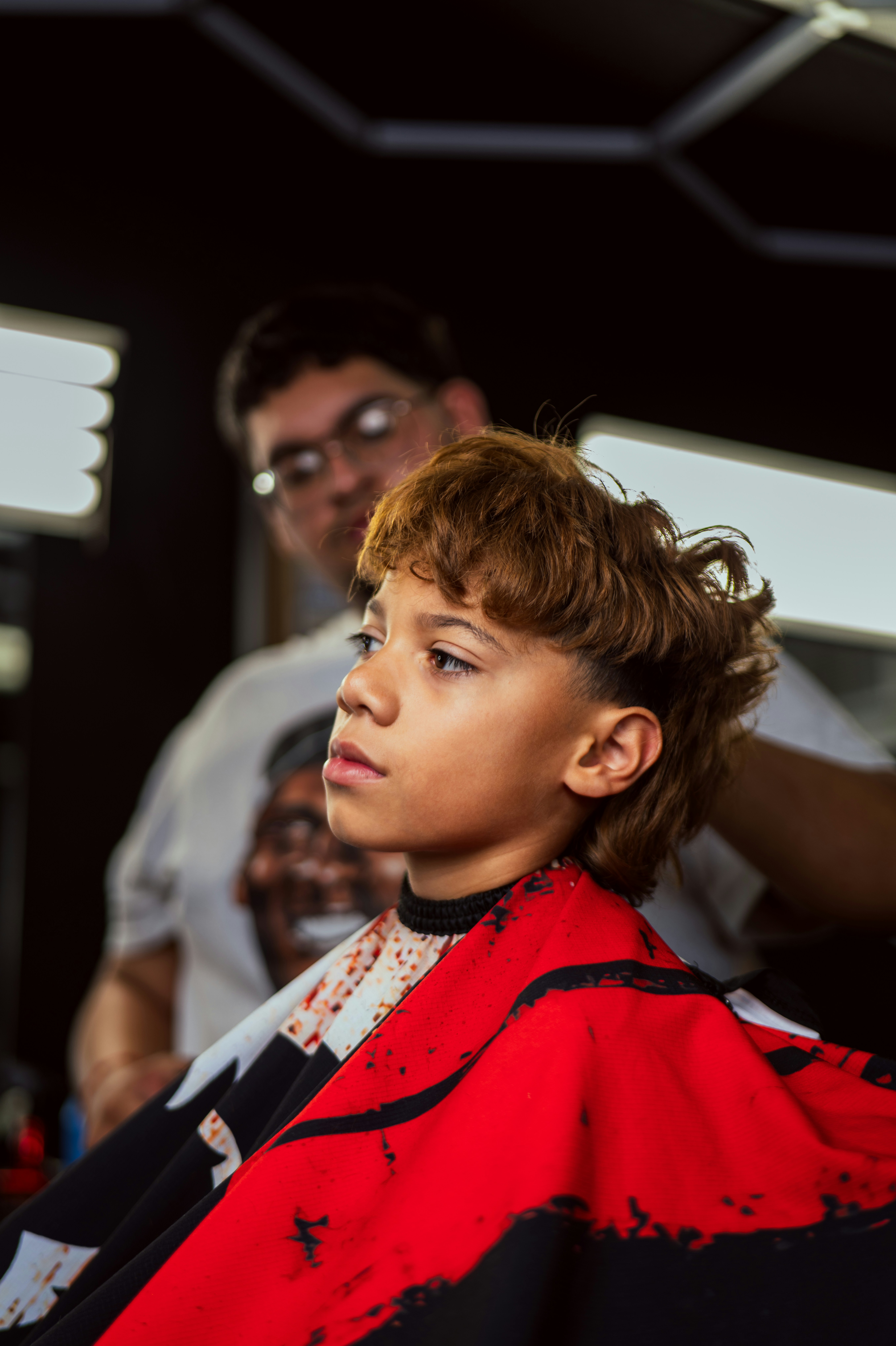 Young Barber in Focus: A Calm Moment Beneath Studio Lights