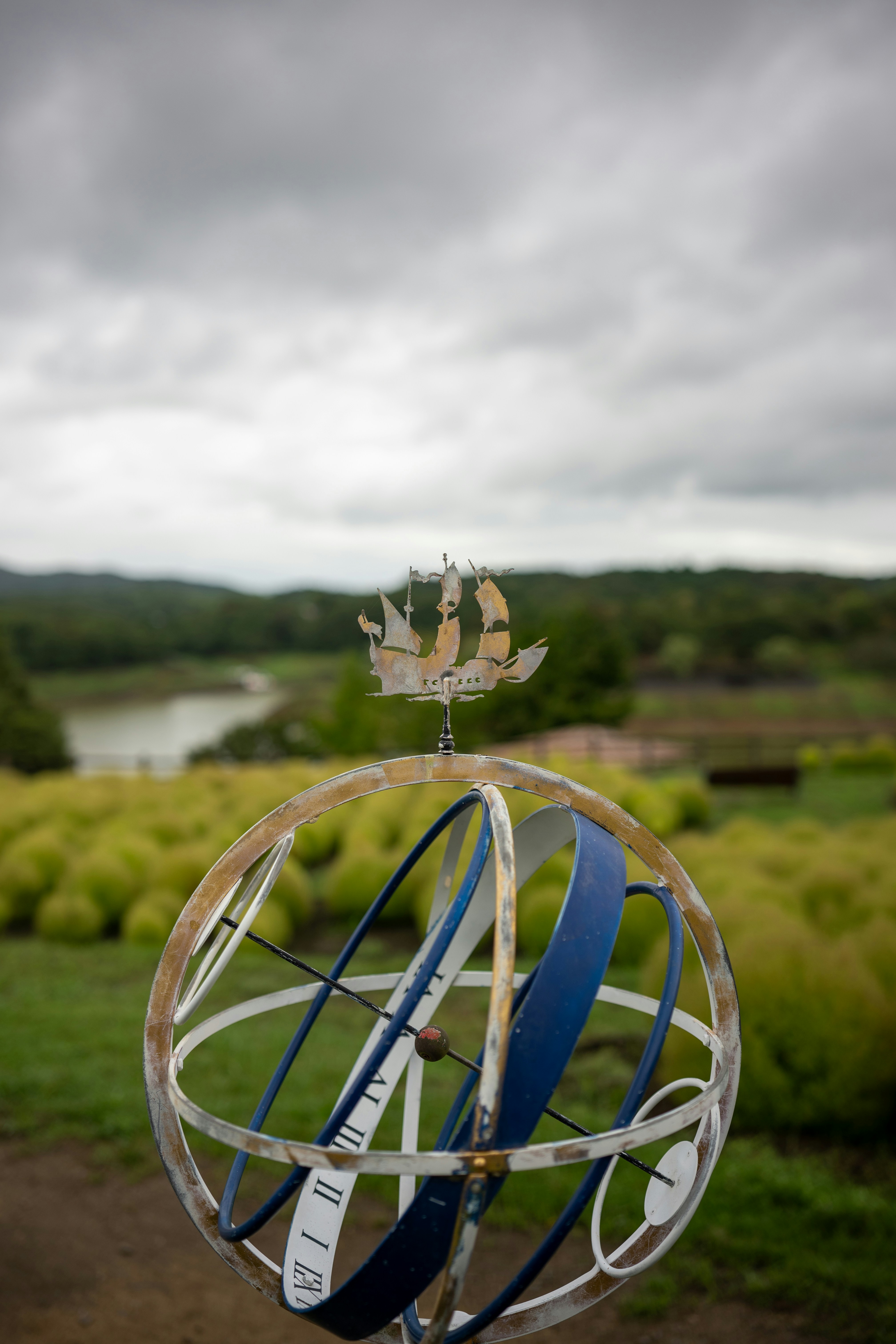 Wind-Spun Orbit: A Weathered Armillary Under overcast skies