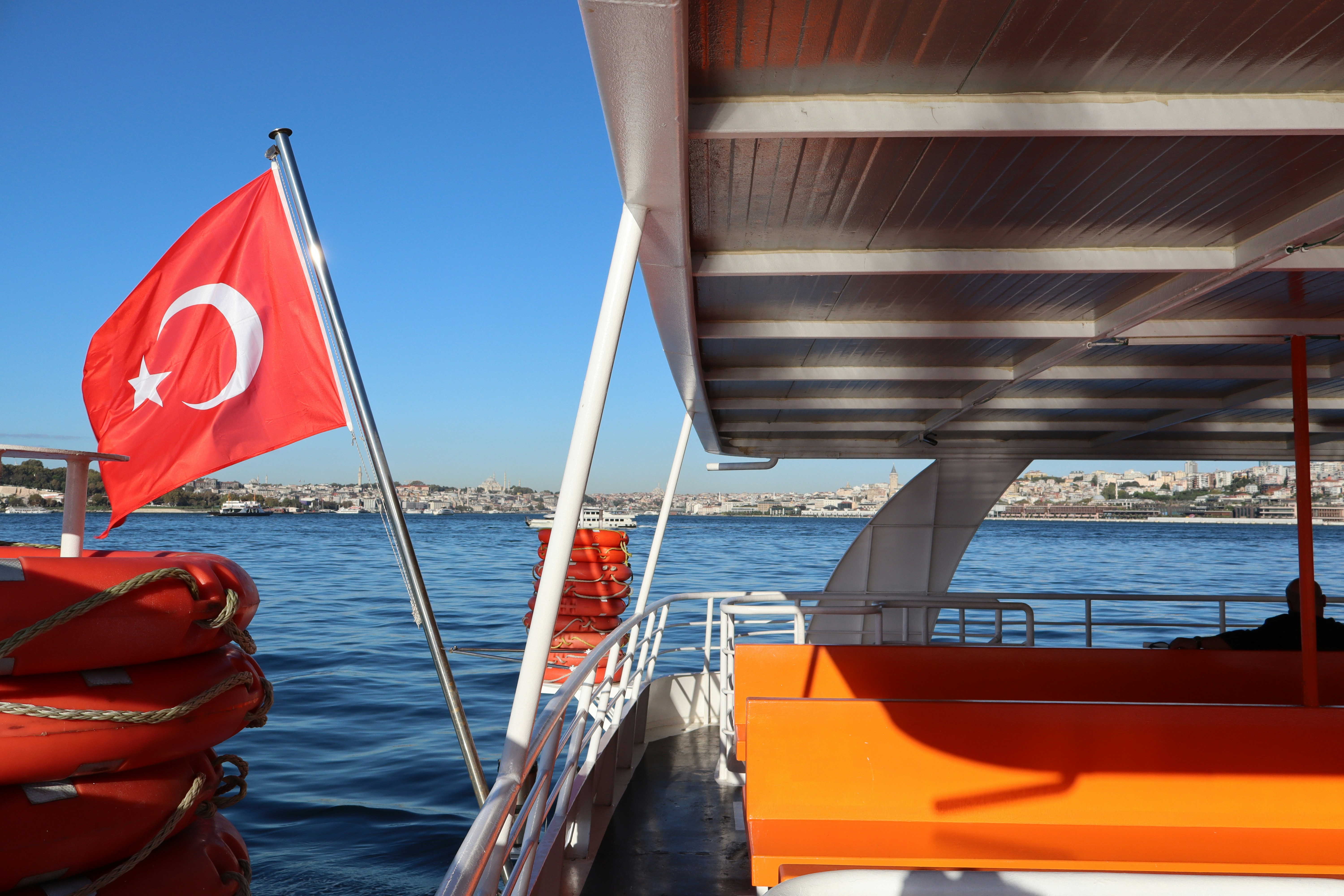 Flag and deck of a passenger ferry gliding over calm blue water