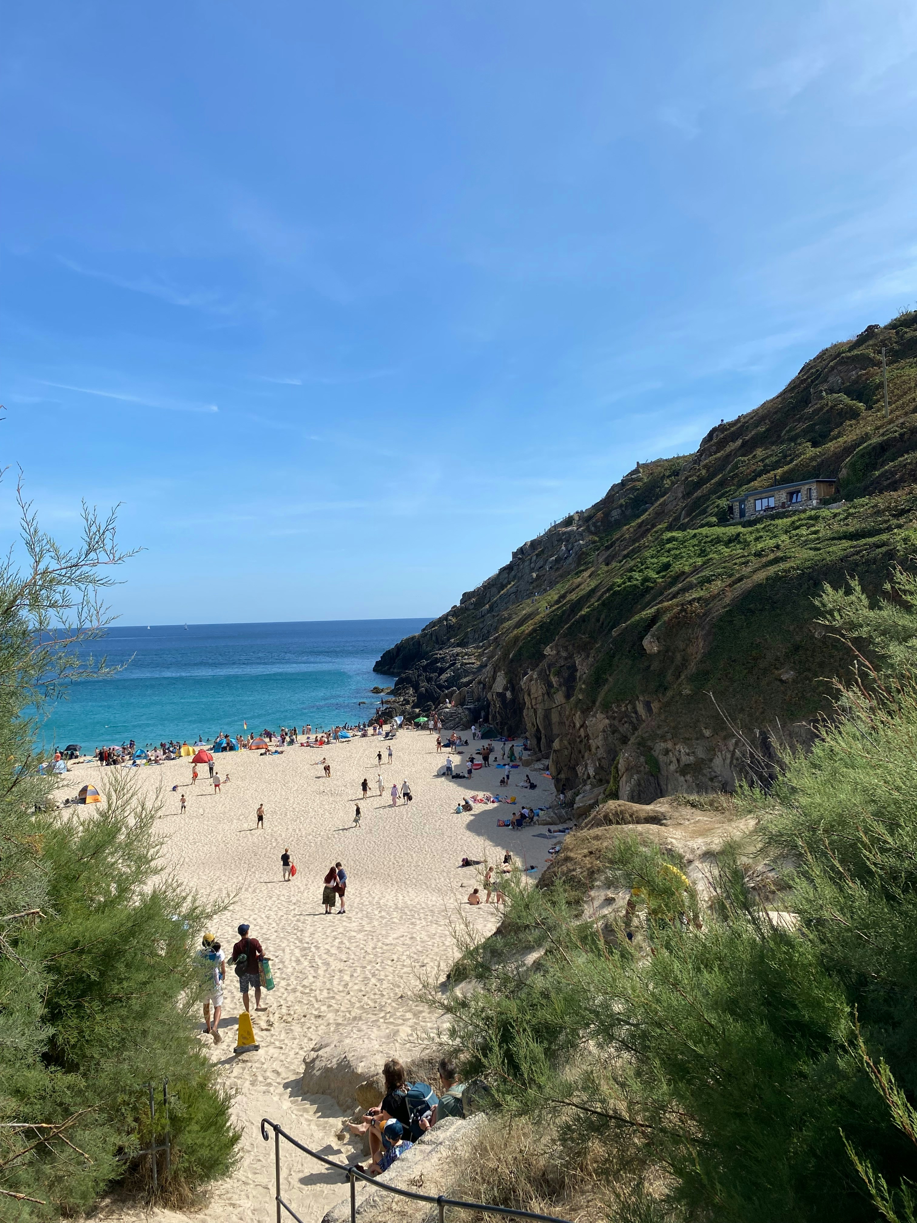 Sunlit Cove: Beachgoers Between Cliff and Sea
