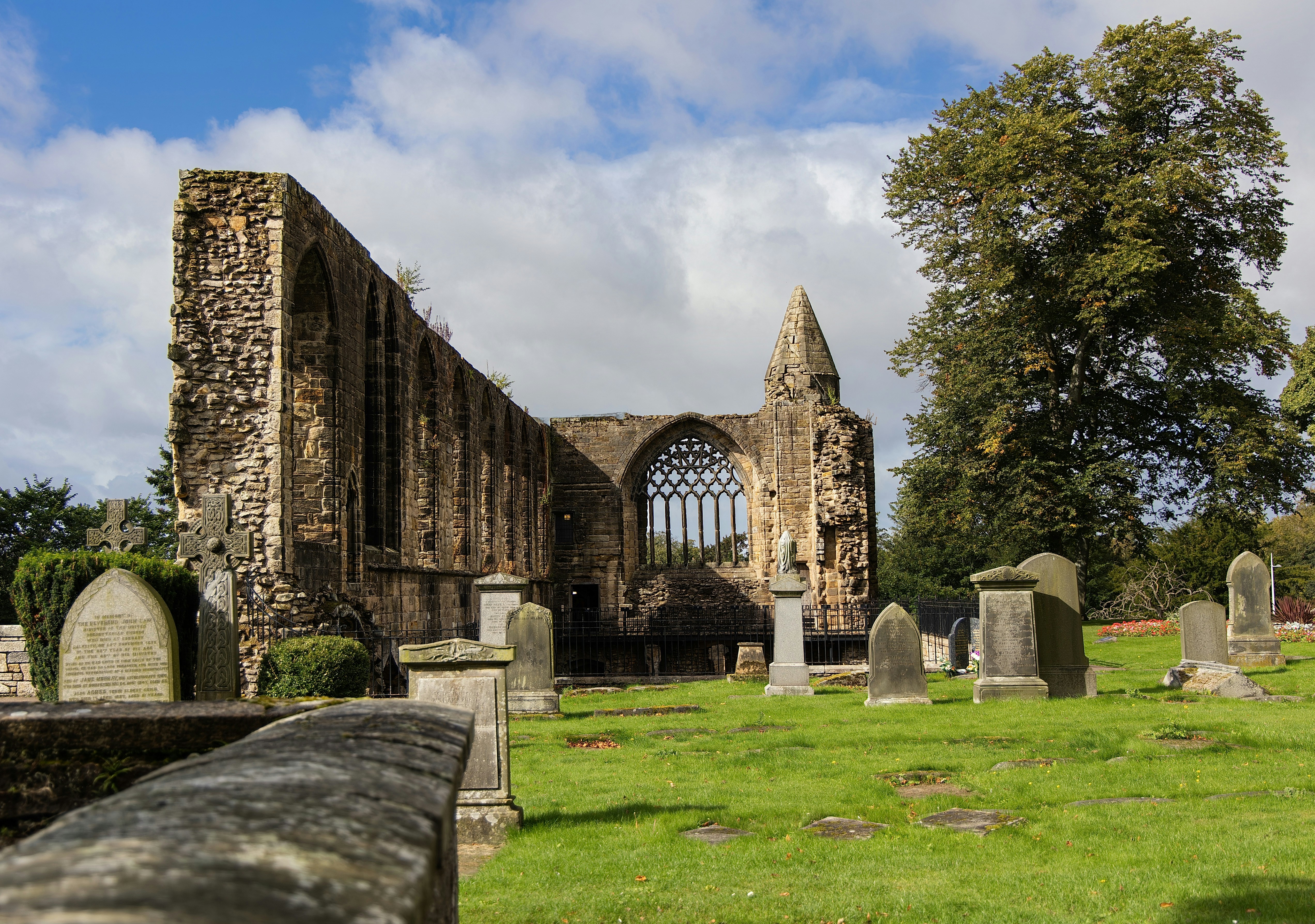 Timeworn Archways and Quiet Gravestones: Abbey Ruin in Sunlit Pasture