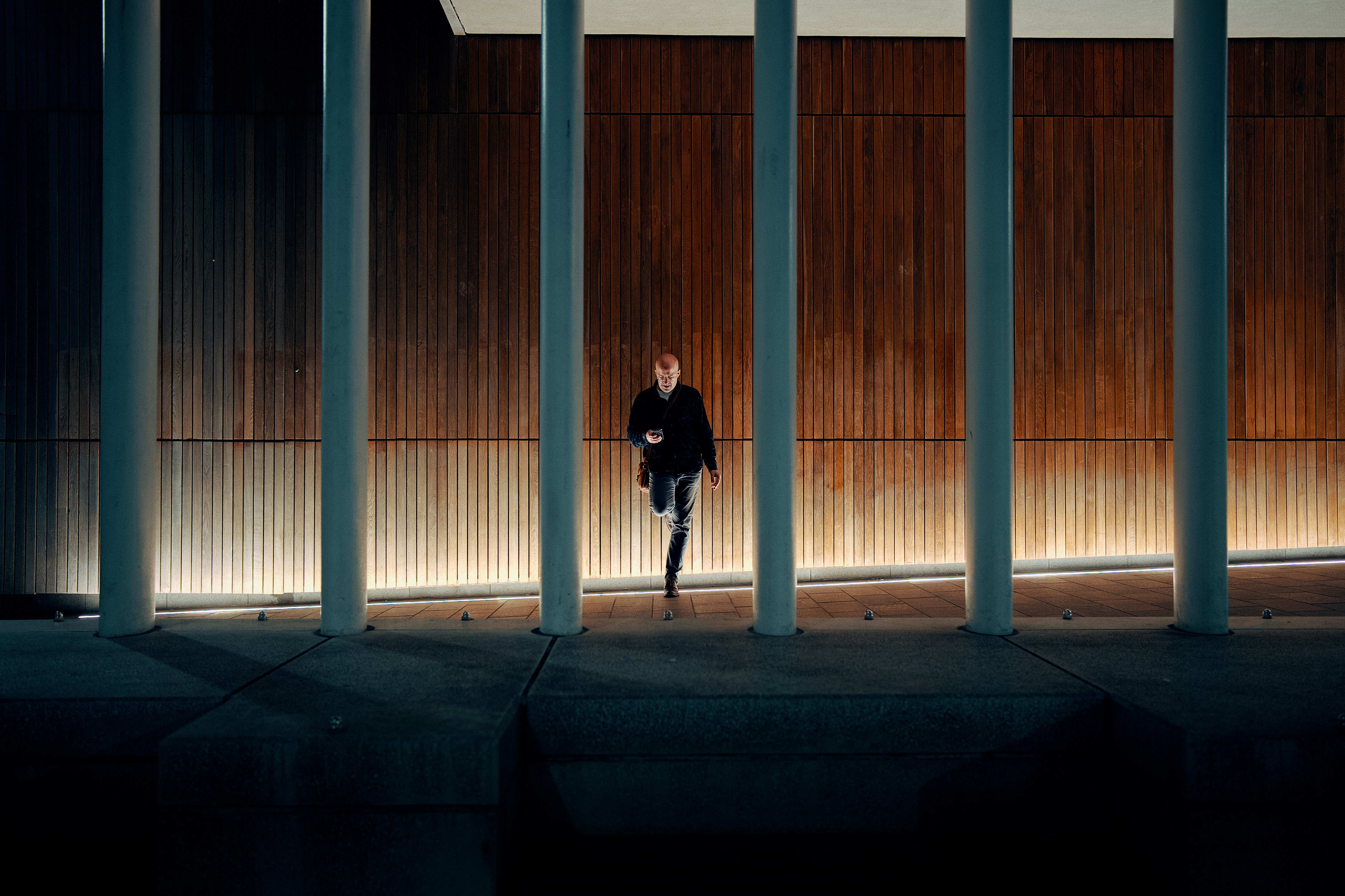 Runner under vertical columns: a quiet chase through a lit corridor