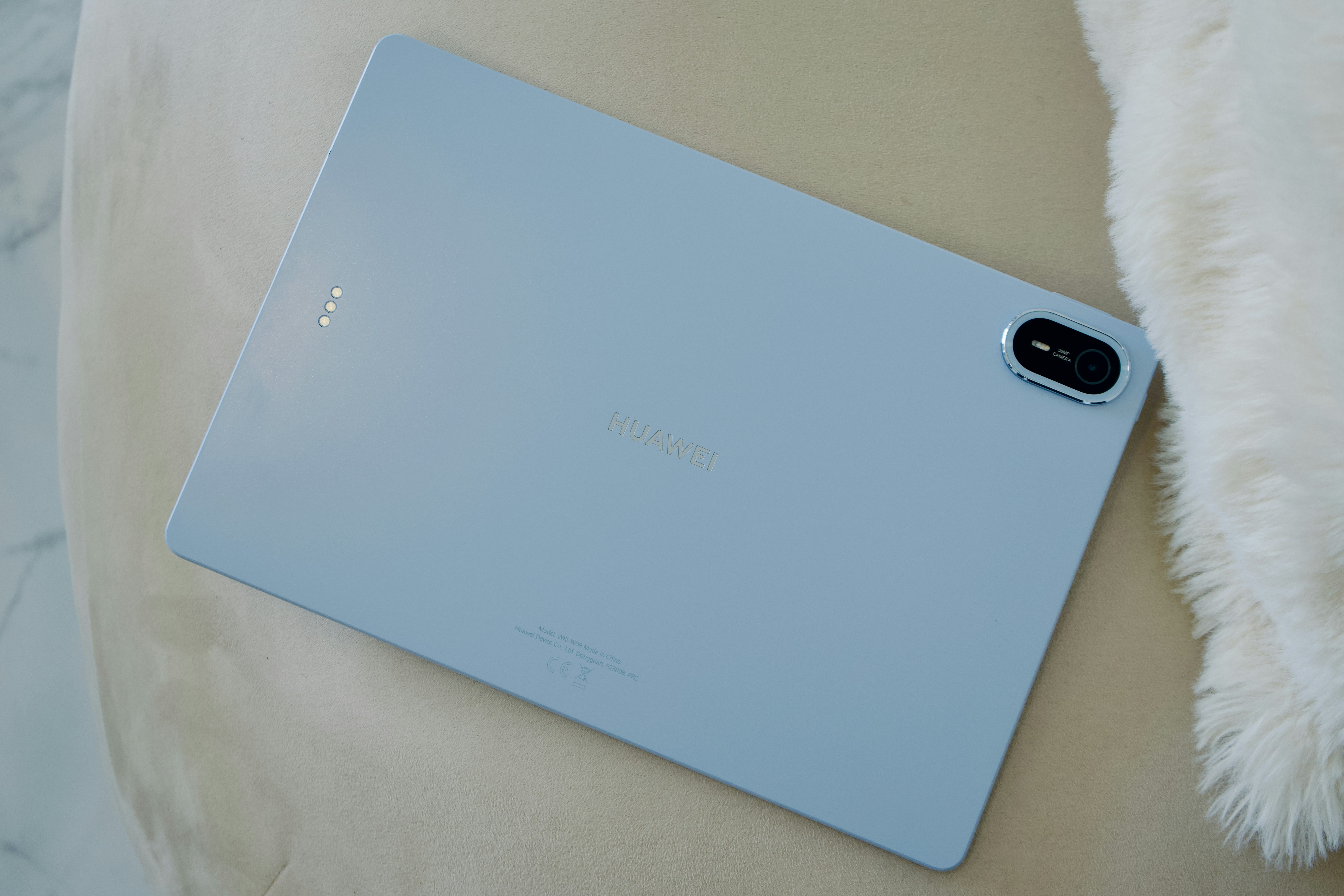 Blue tablet resting on a plush beige surface