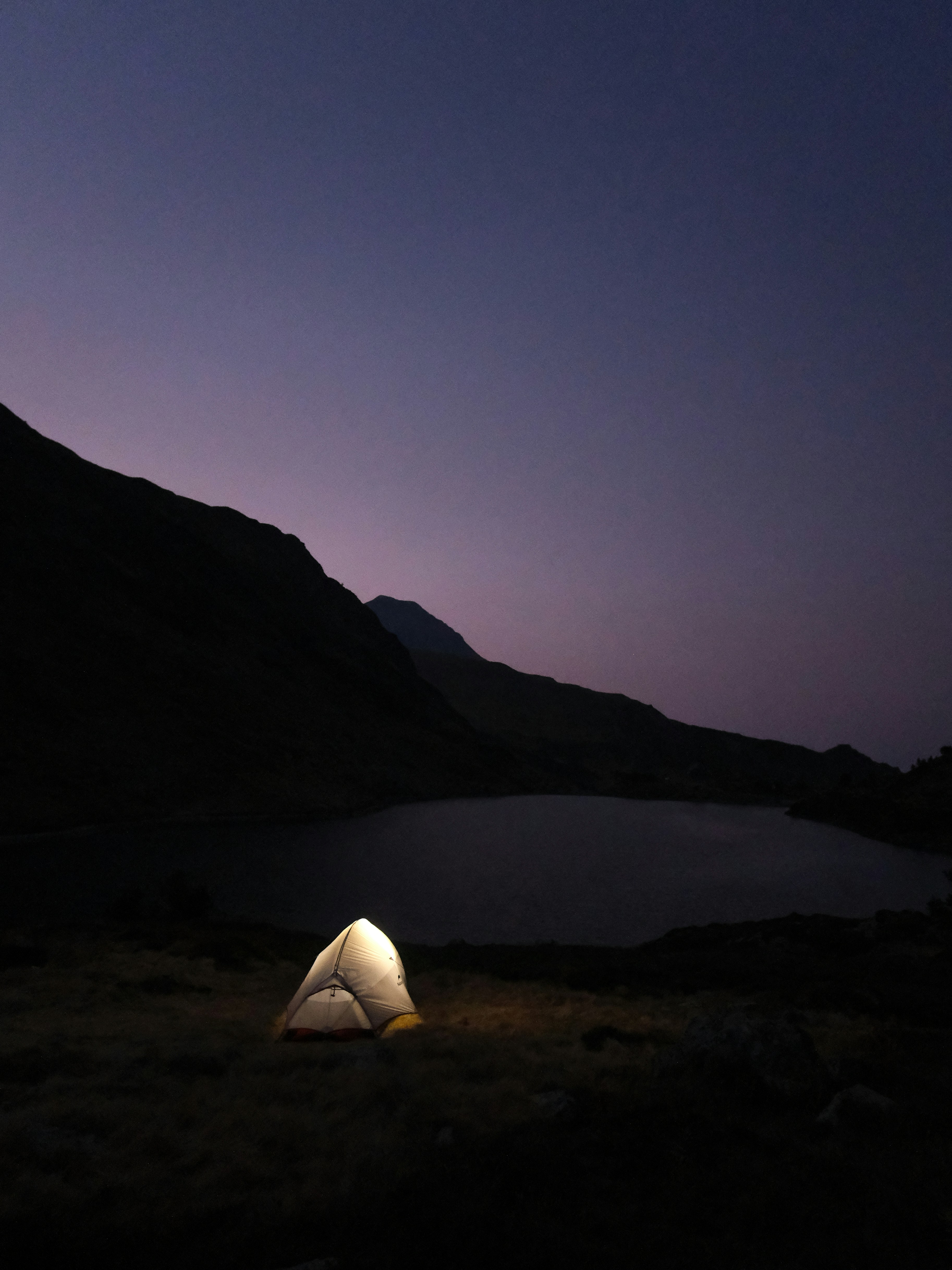 Late-Night Oasis: A Lone Tent Beneath Mountain Shadows