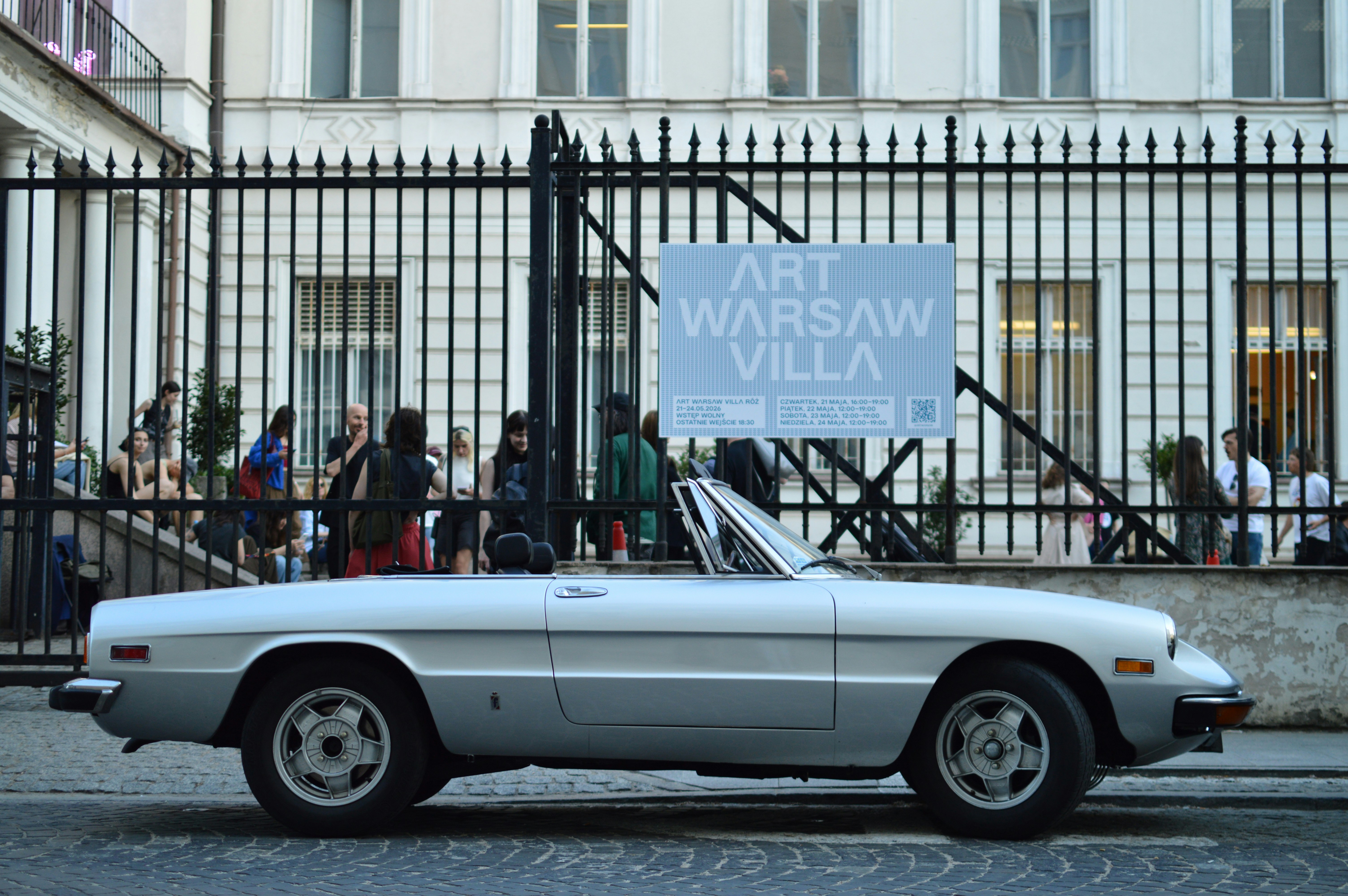 Coastal Classic: A Silver Convertible Traverses a Historic Warsaw Street