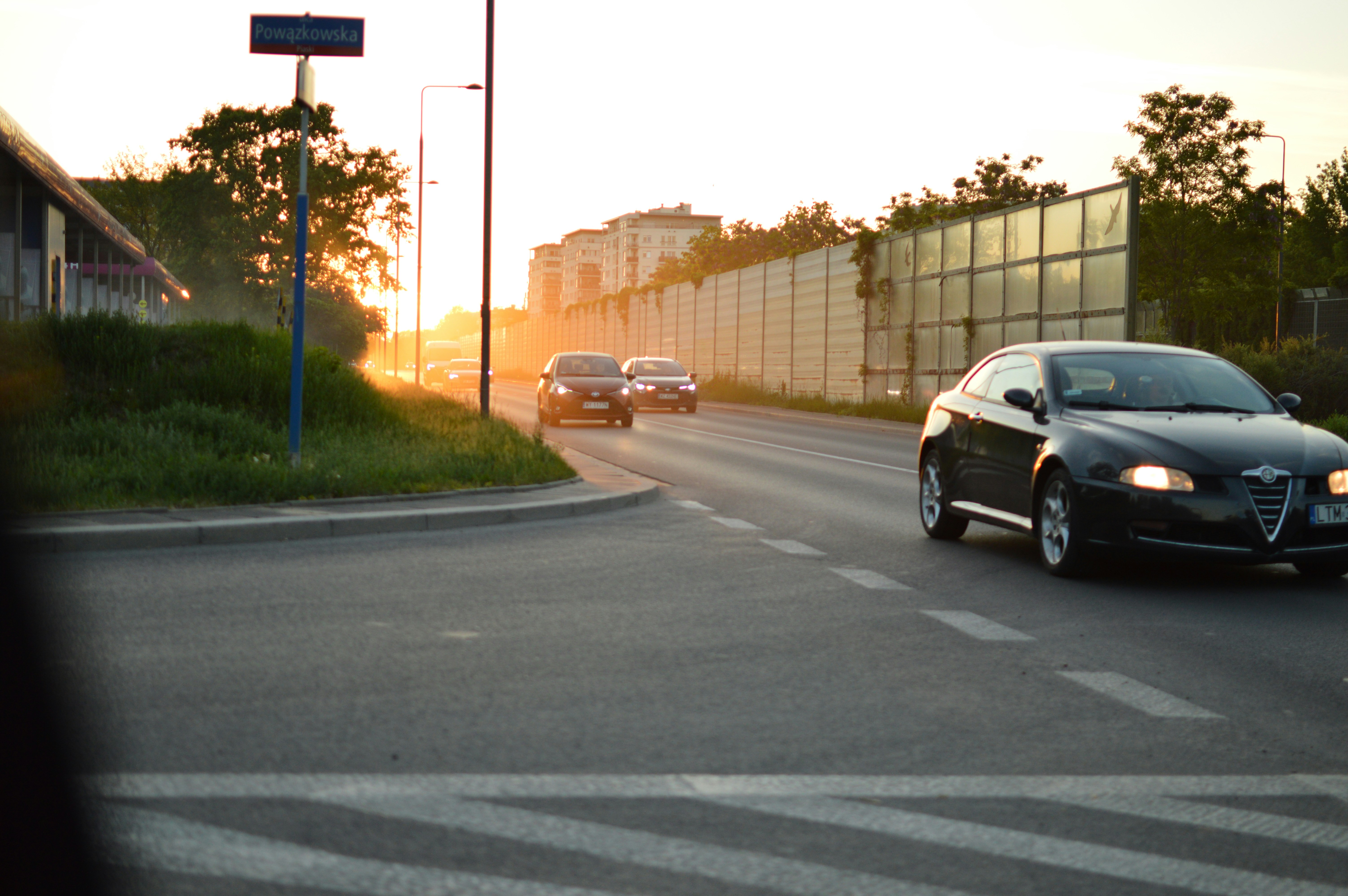 Sunlit street sprint: a black coupe leads the way toward the horizon