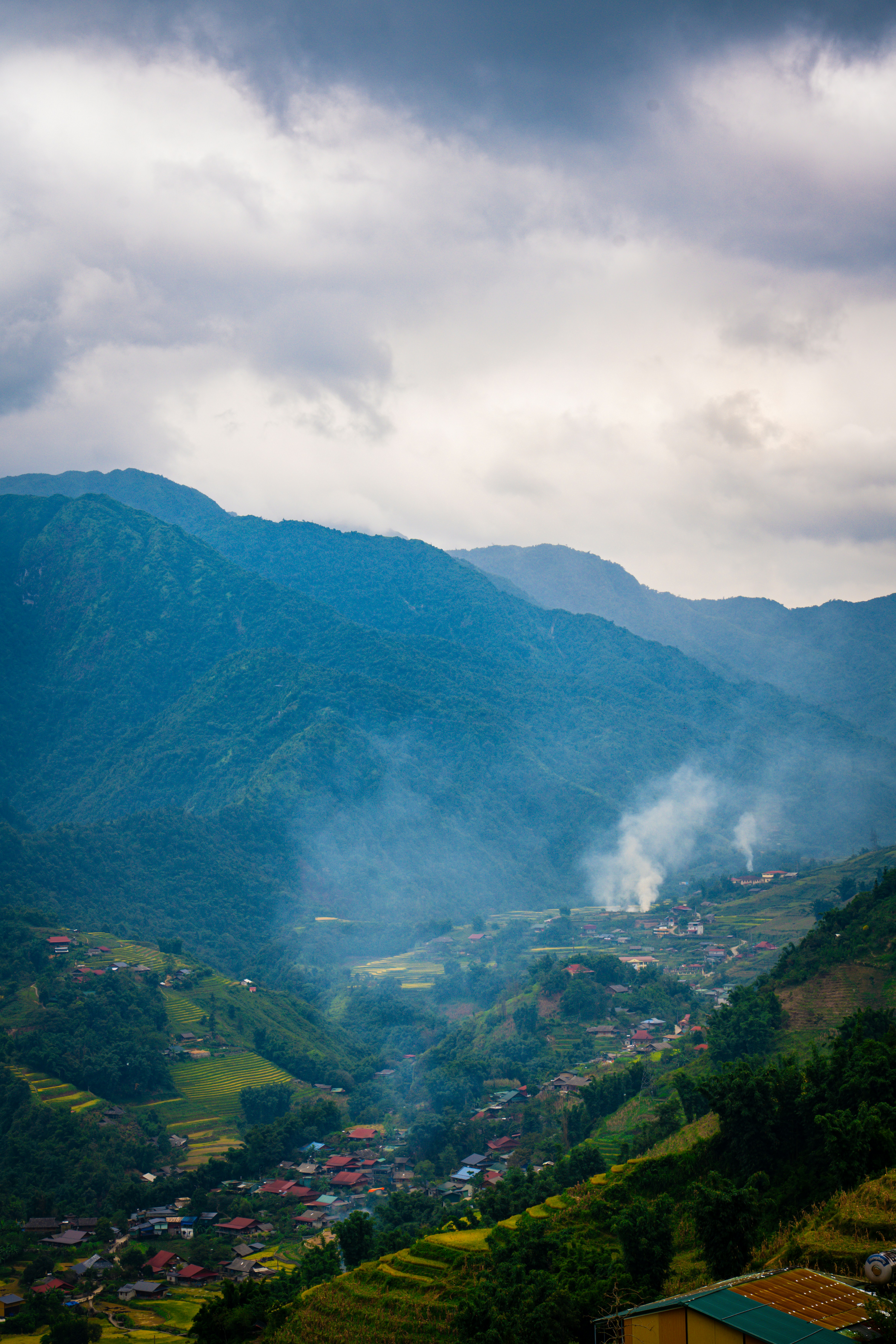 Misty Highlands: Smoke over Terraced Villages Beneath Fierce Peaks