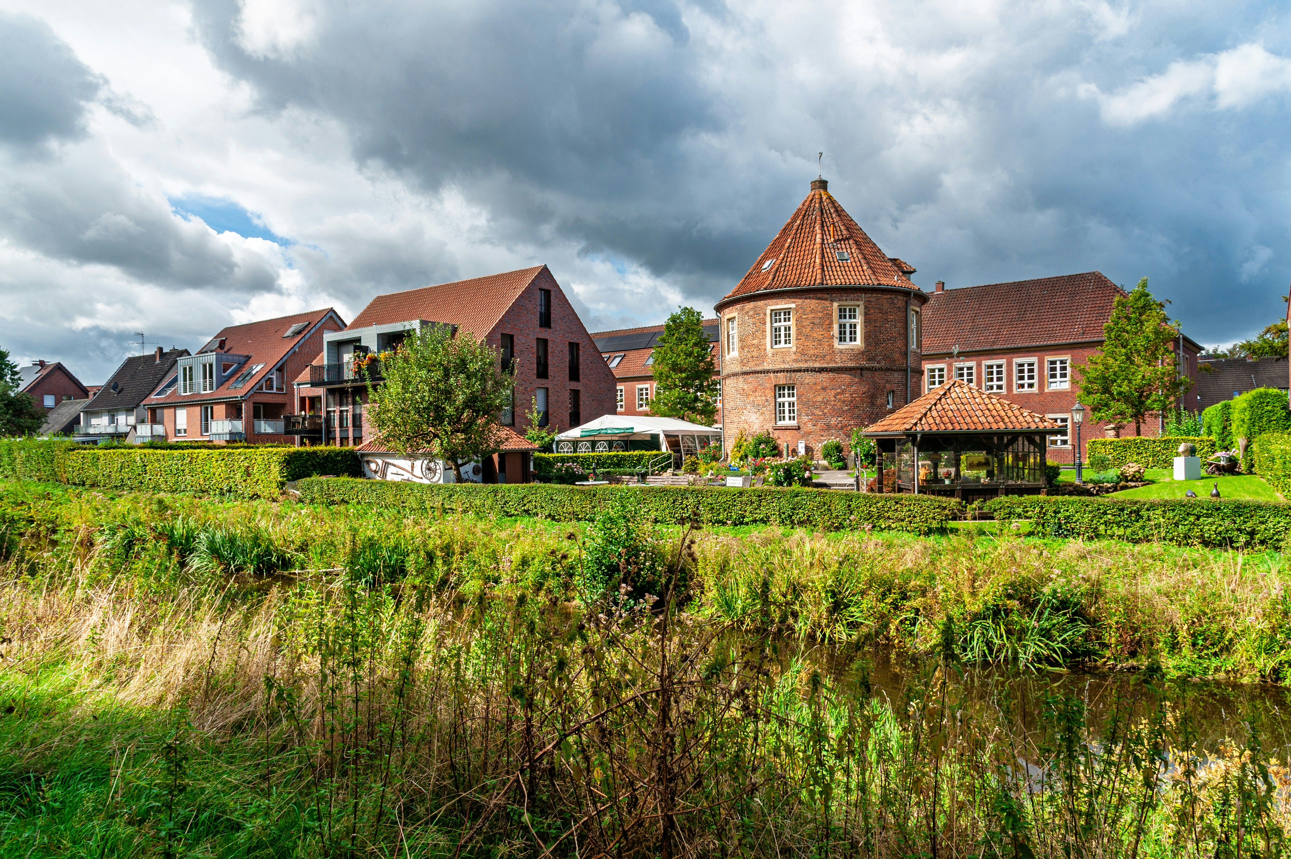 Village by the Water: Turreted Red-Brick Charm Under Broad Skies